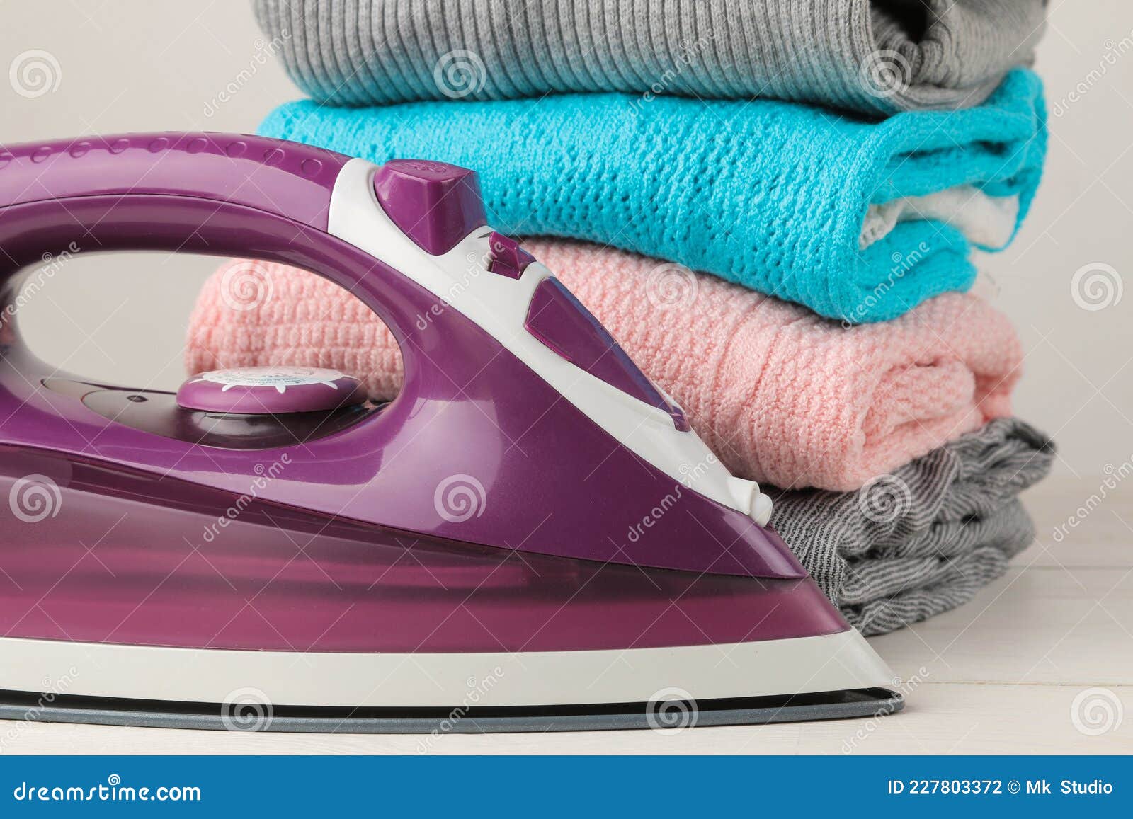 Iron and a Stack of Colored Clothes on a White Background. Ironing of ...