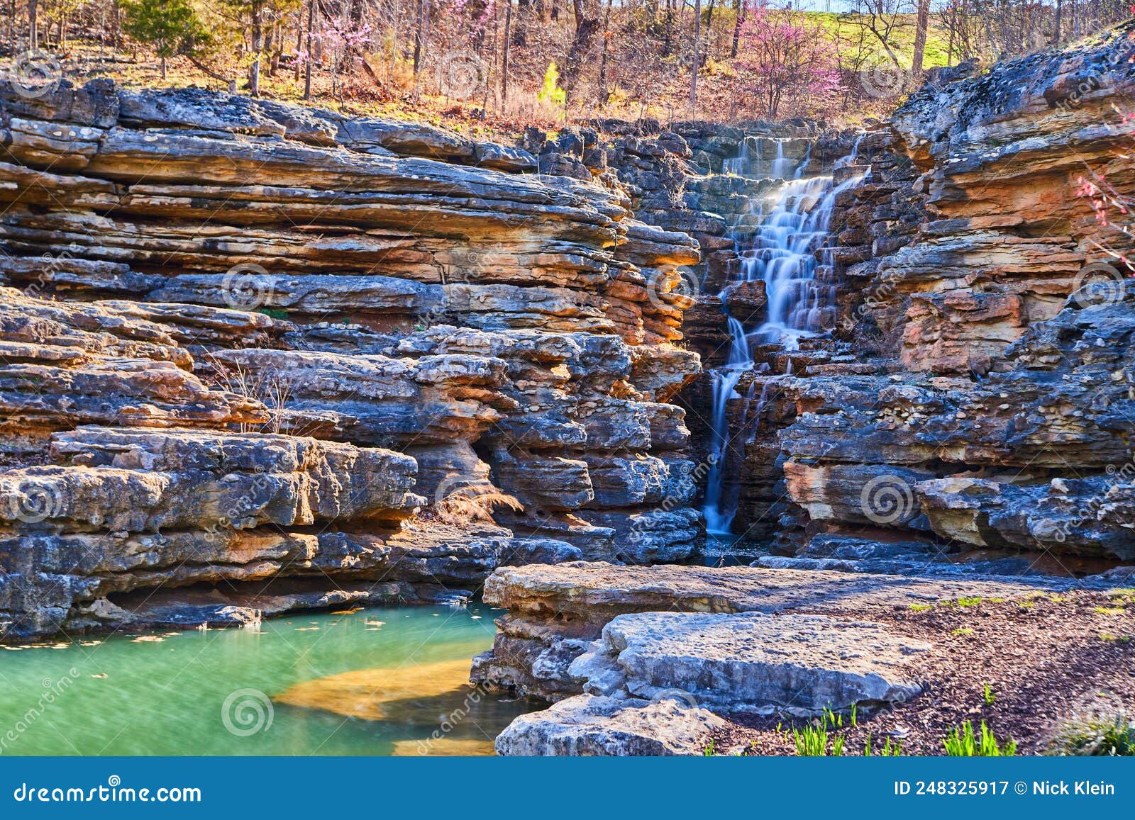 Jagged Rocks Featuring Simple Waterfall into Teal Waters Stock Image ...