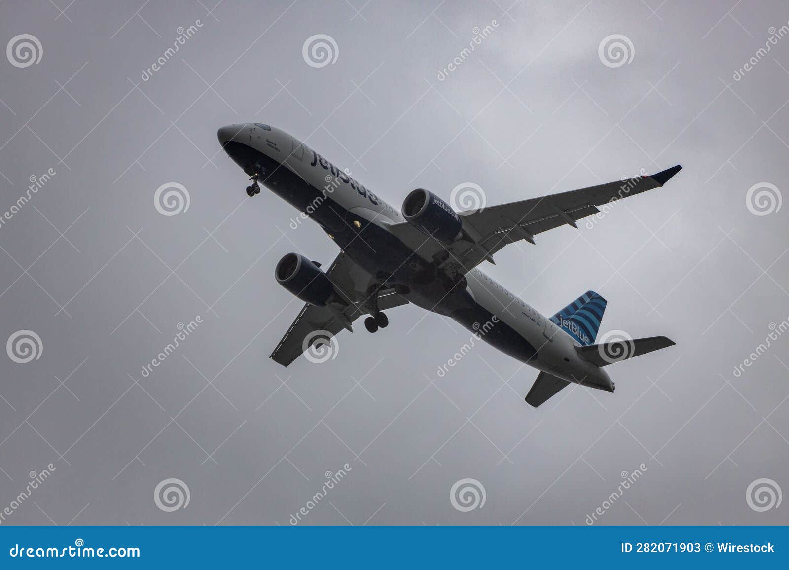 JetBlue Airbus A220 Aircraft Flying through the Sky on a Grey Cloudy ...