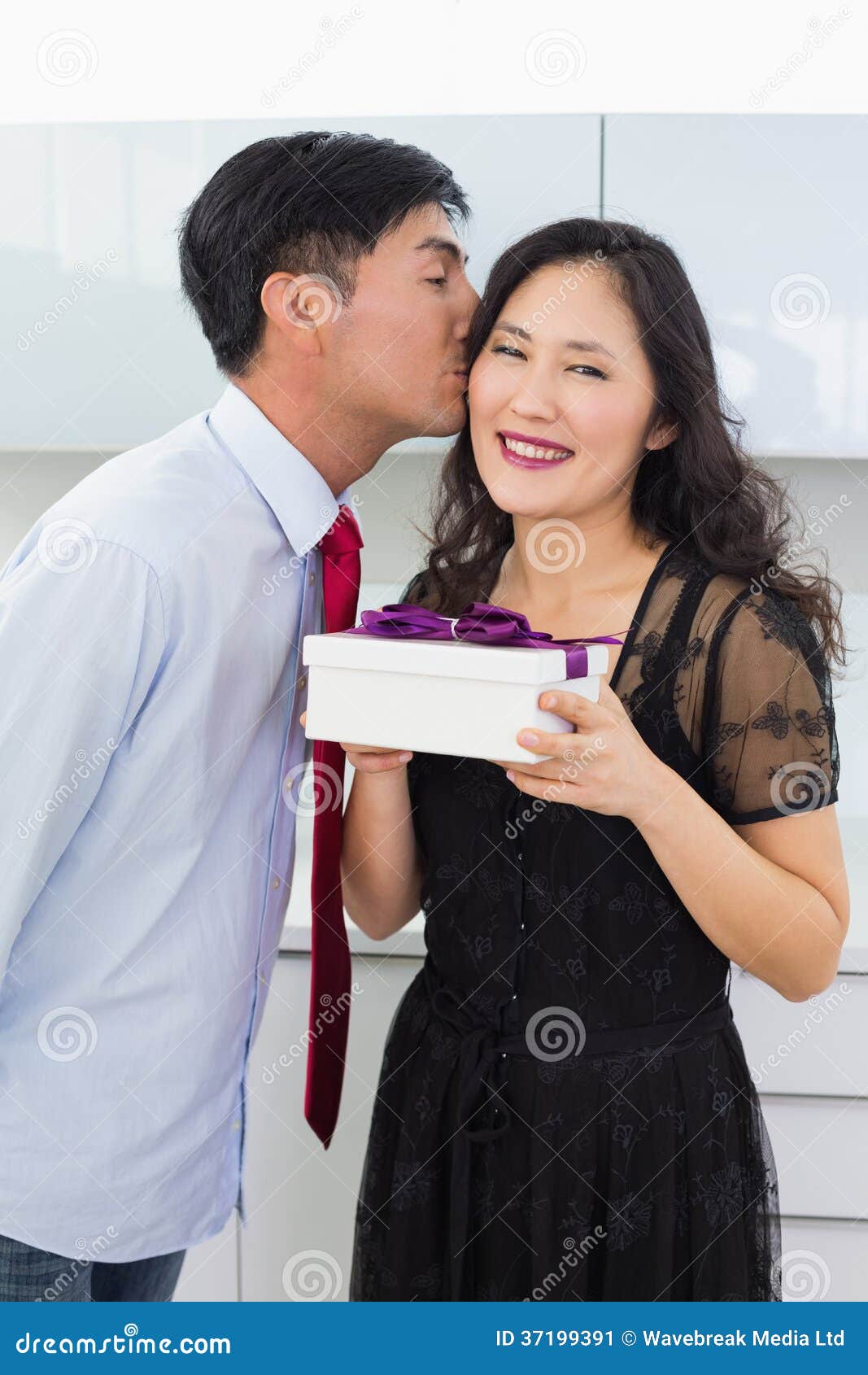 Jeune Homme Embrassant Une Femme Comme Il Lui Donne Un Boîte Cadeau