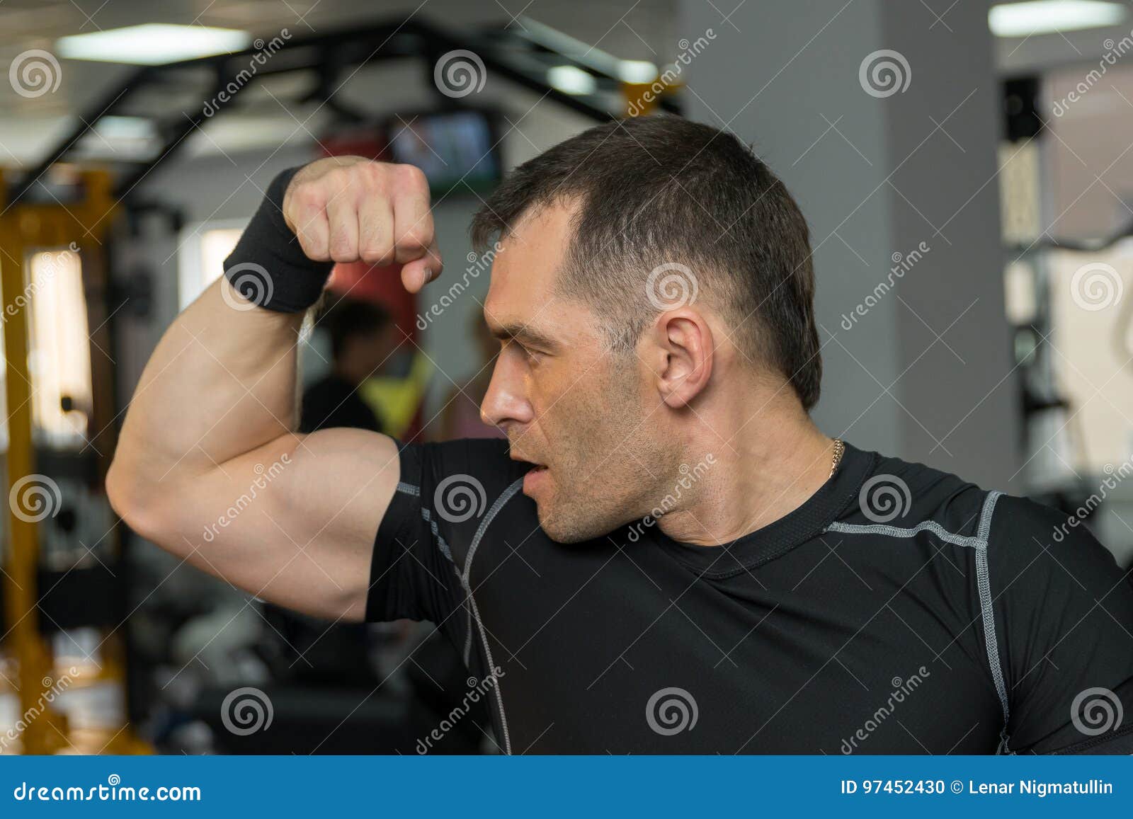 Jeune Homme Musculaire Montrant Son Biceps Dans Le Gymnase Photo Stock