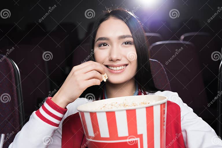 Jong Aziatisch Meisje Die Popcorn Eten En Op Film Letten Stock Foto