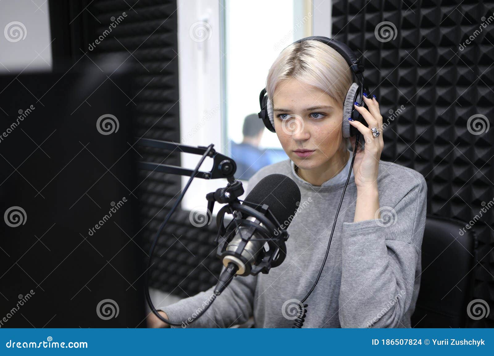 Journalist Sitting in Front of a Microphone and Broadcasting at a Radio ...