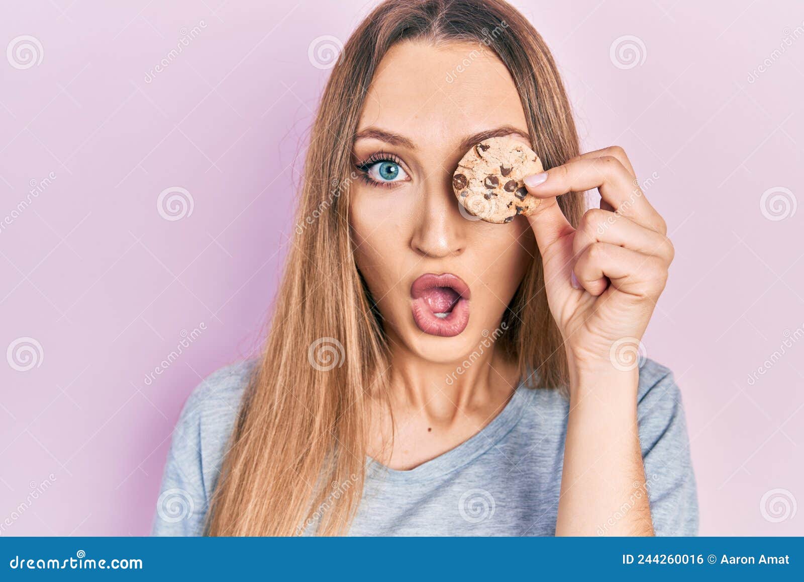 Jovencita Rubia Sosteniendo Una Galleta Sobre El Ojo Asustada Y