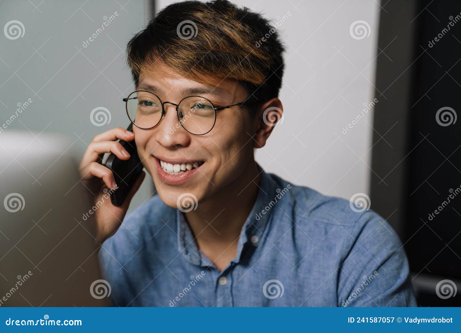 Joyful Asian Guy Talking on Cellphone while Working with Laptop Stock ...