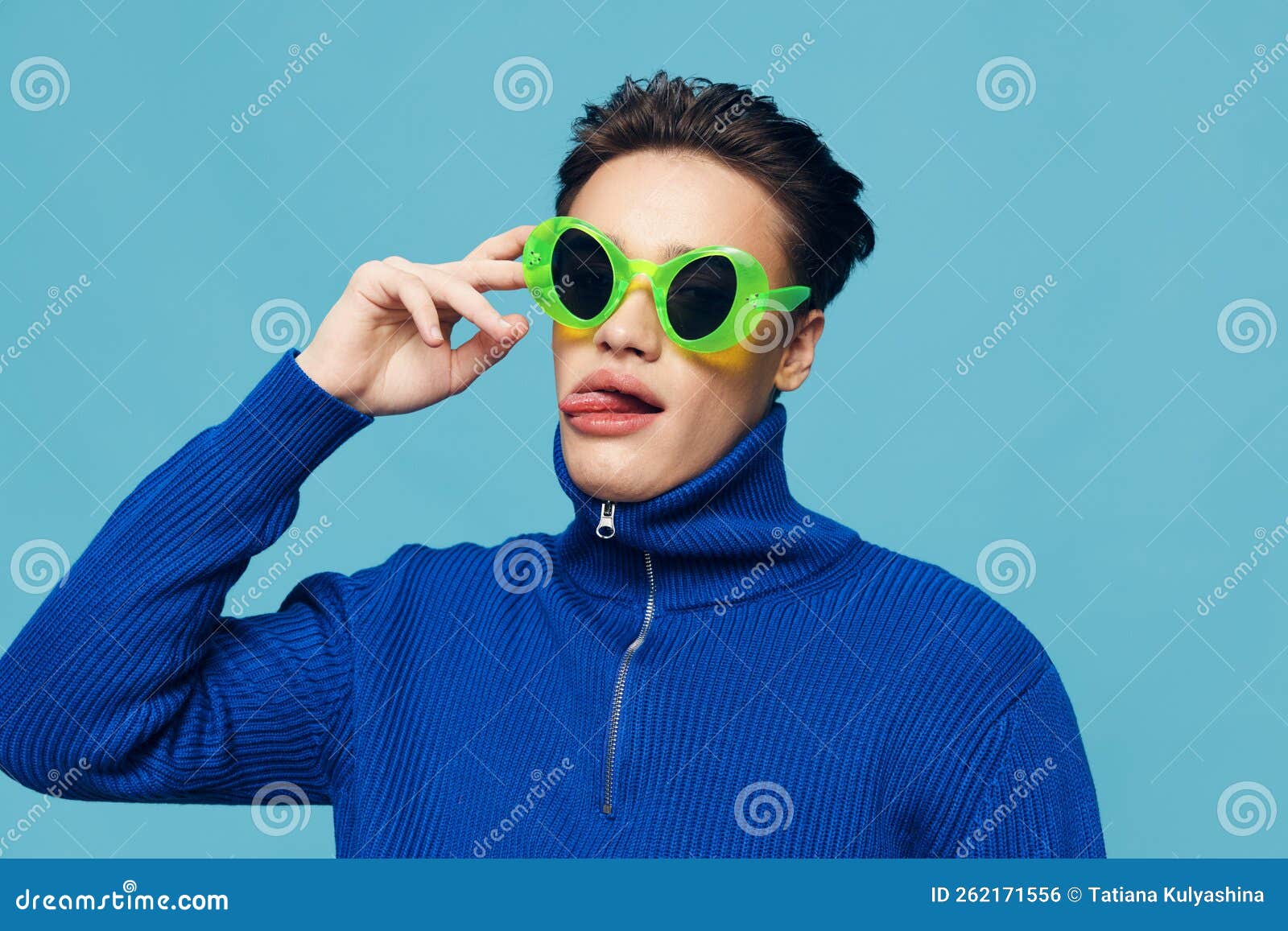 A Joyful Man Stands On A Light Blue Background In A Blue Zip Up Jacket