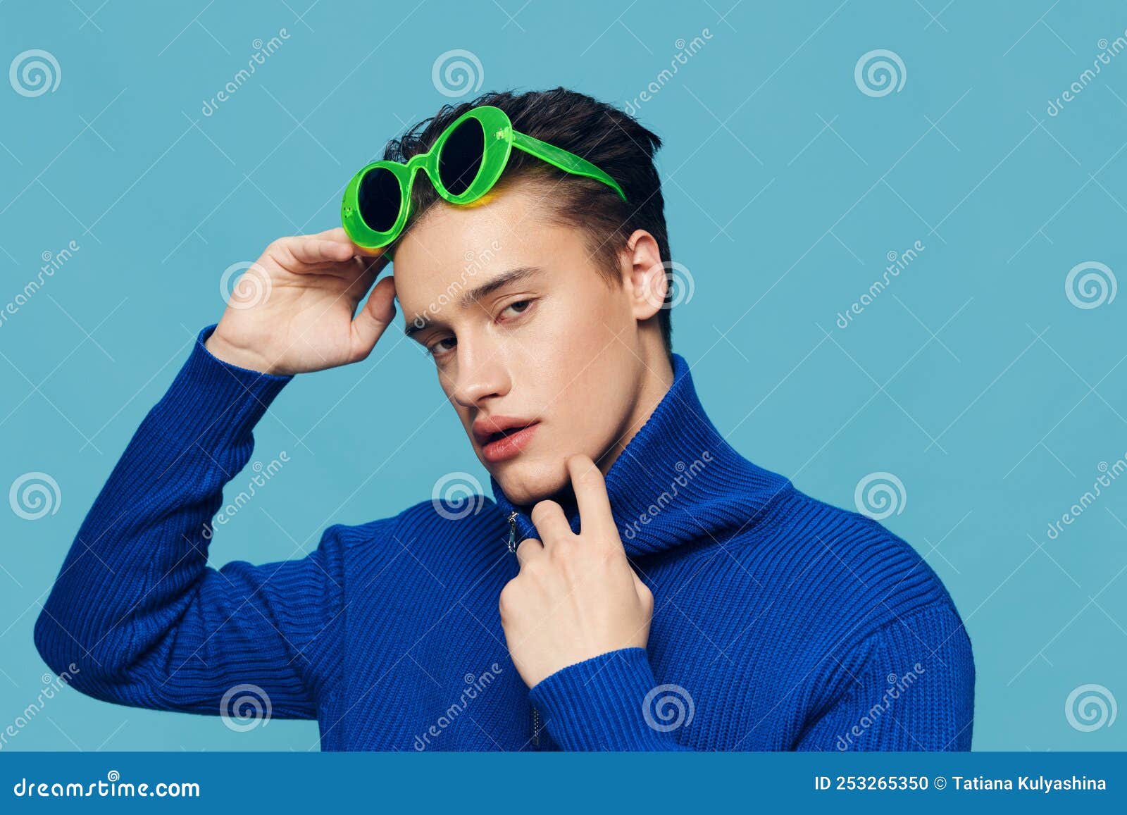 A Joyful Man Stands On A Light Blue Background In A Blue Zip Up Jacket