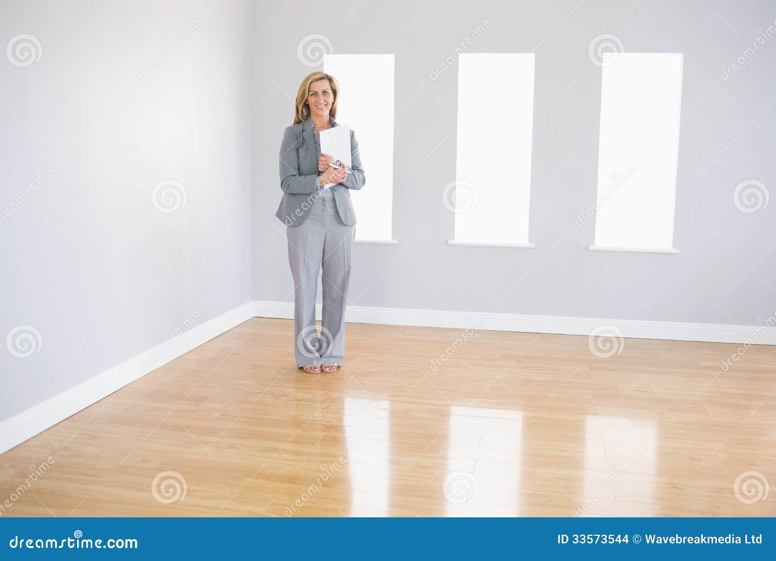 Joyful Realtor Standing in a Room Holding Documents Stock Photo - Image ...