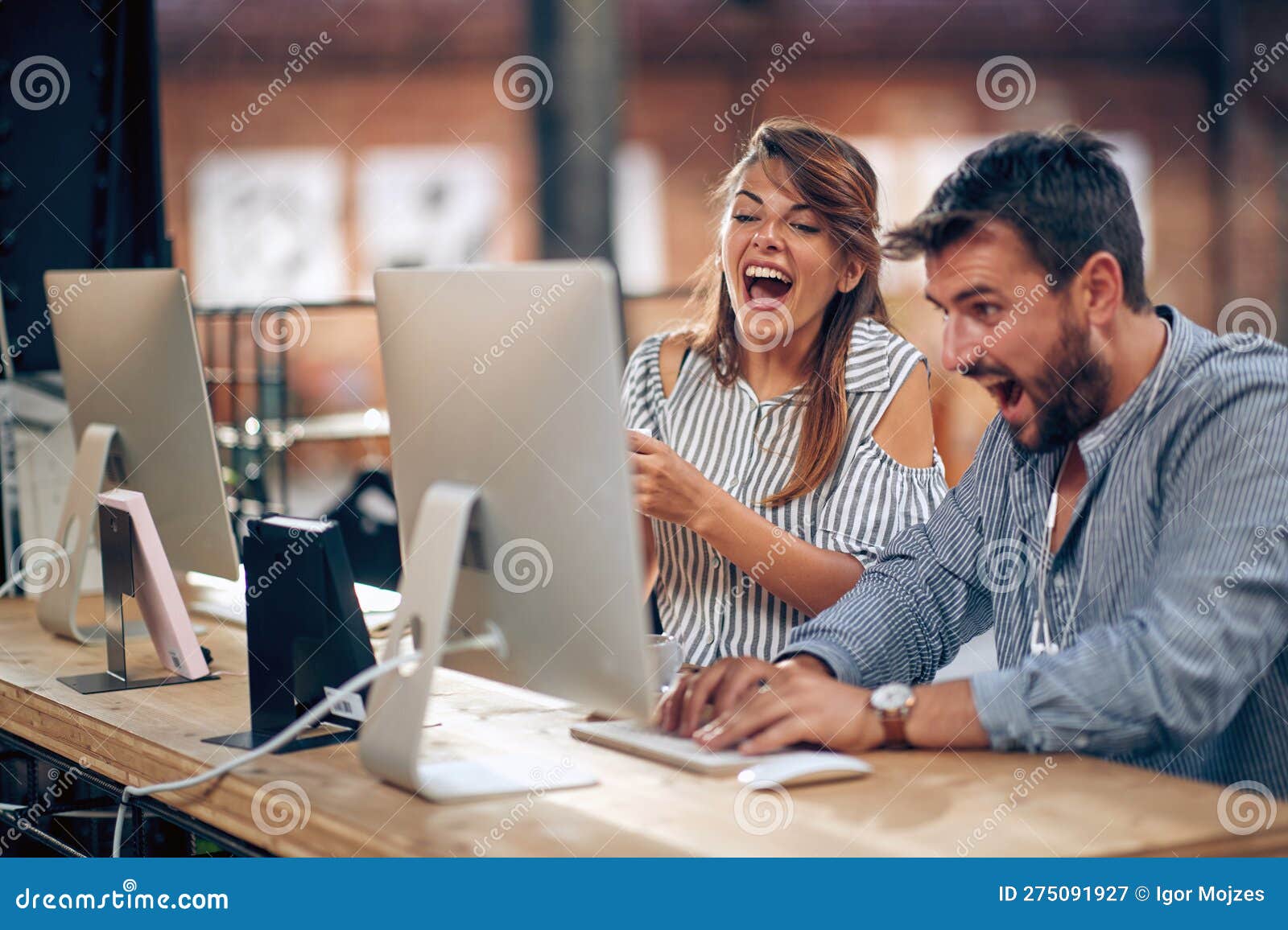 Joyful Young Colleagues Working and Looking at Computer Screen Together ...