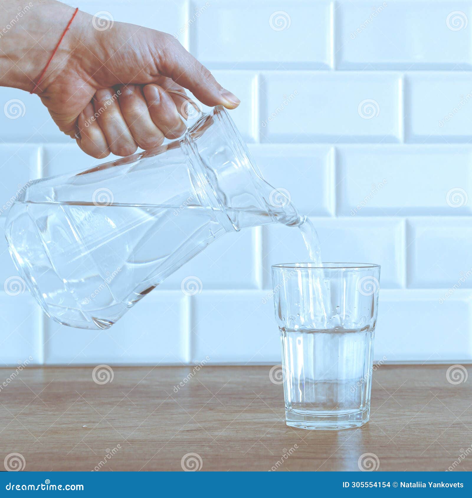 A Glass of Clean Water on the Kitchen Table. a Jug of Water in a Man ...