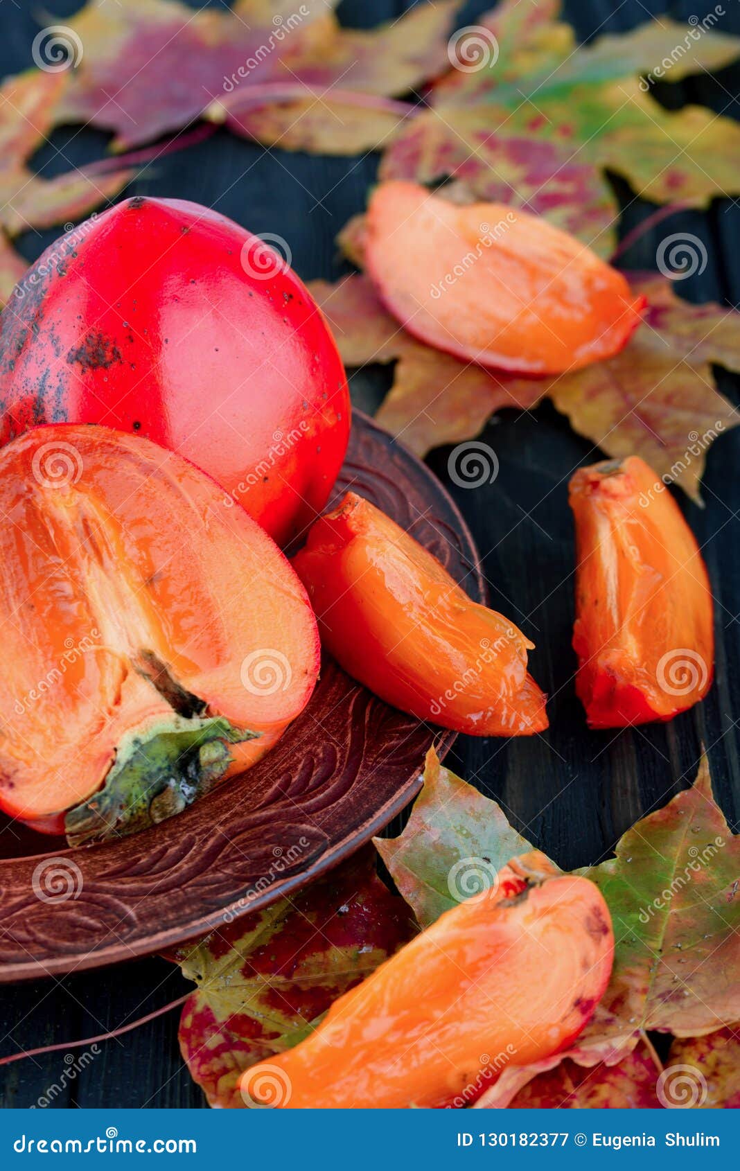 Juicy Munch among the Autumn Leaves. Persimmon in a Clay Plate. Stock ...