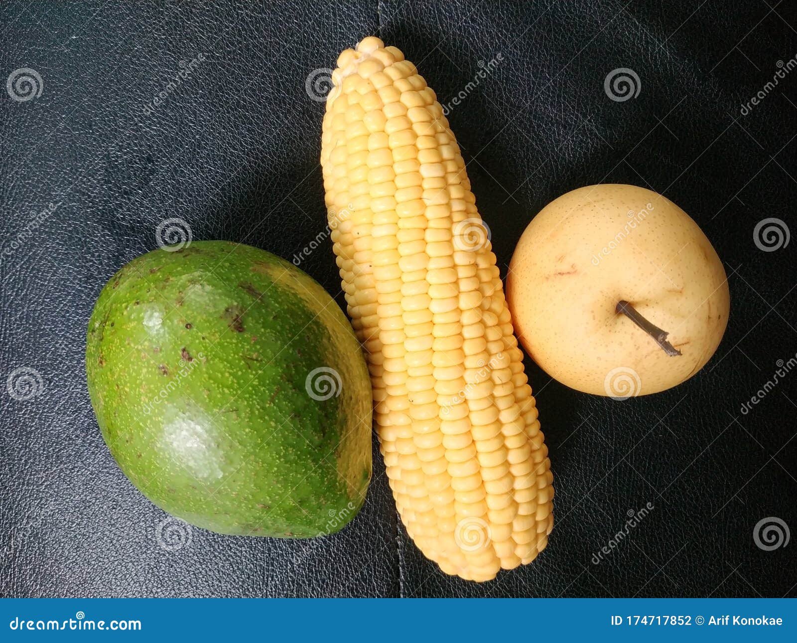 Jumbo Sized Corn and Pear Fruit and Avocado on Black Leather Board ...