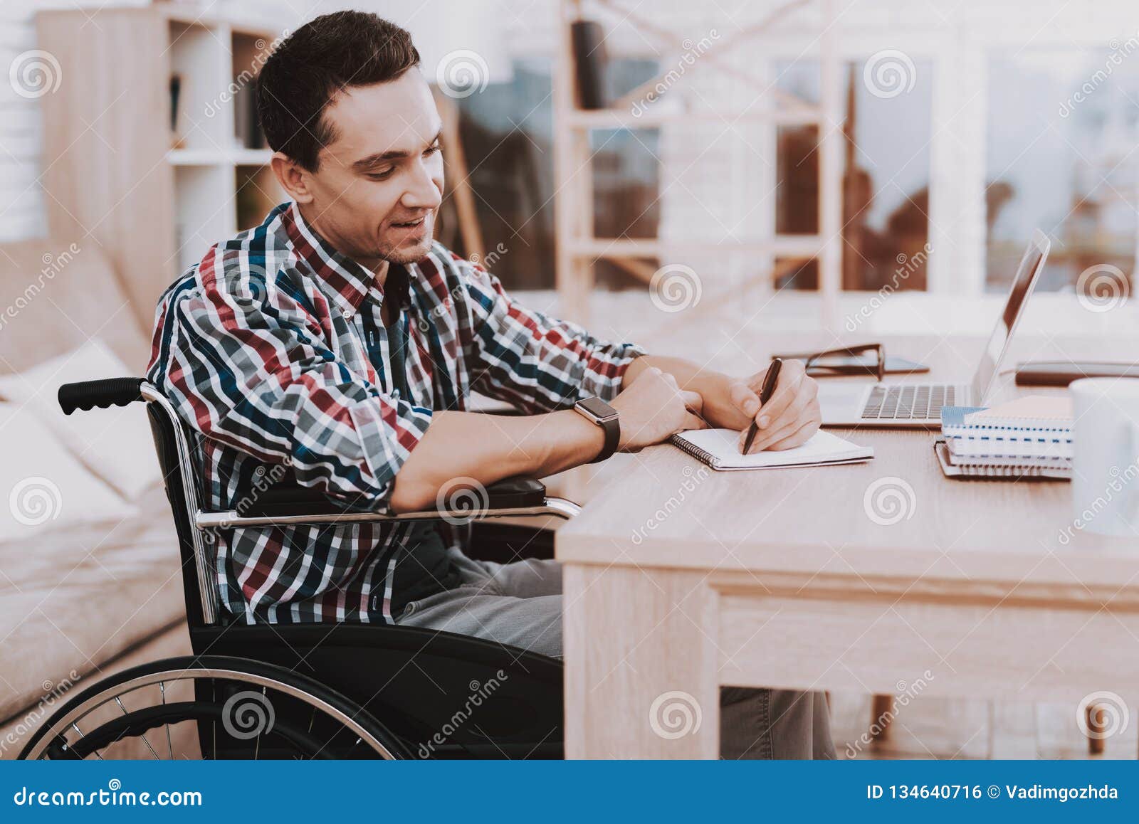Junger Behinderter Mann Auf Dem Rollstuhl, Der Zu Hause Arbeitet ...
