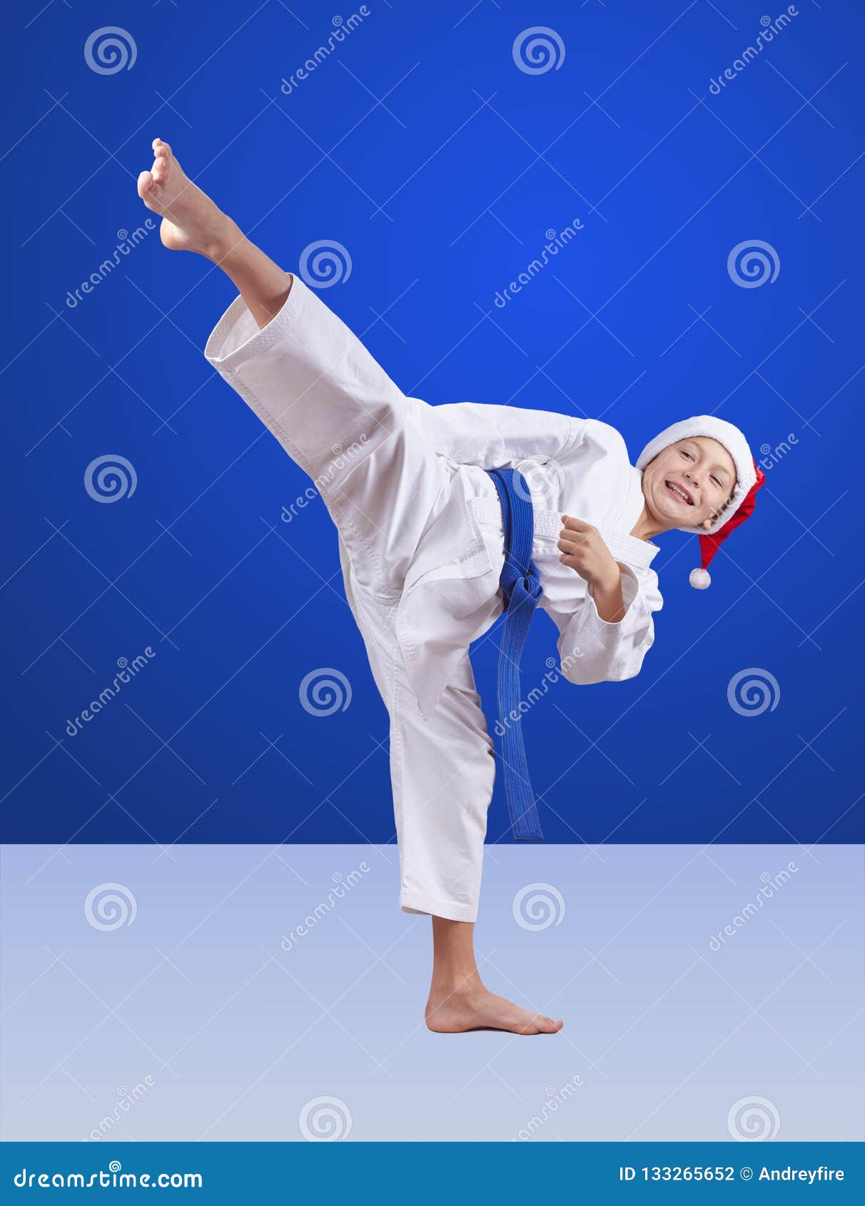 Karateka in the Cap of Santa Claus Hits a Kick on a Blue Background ...