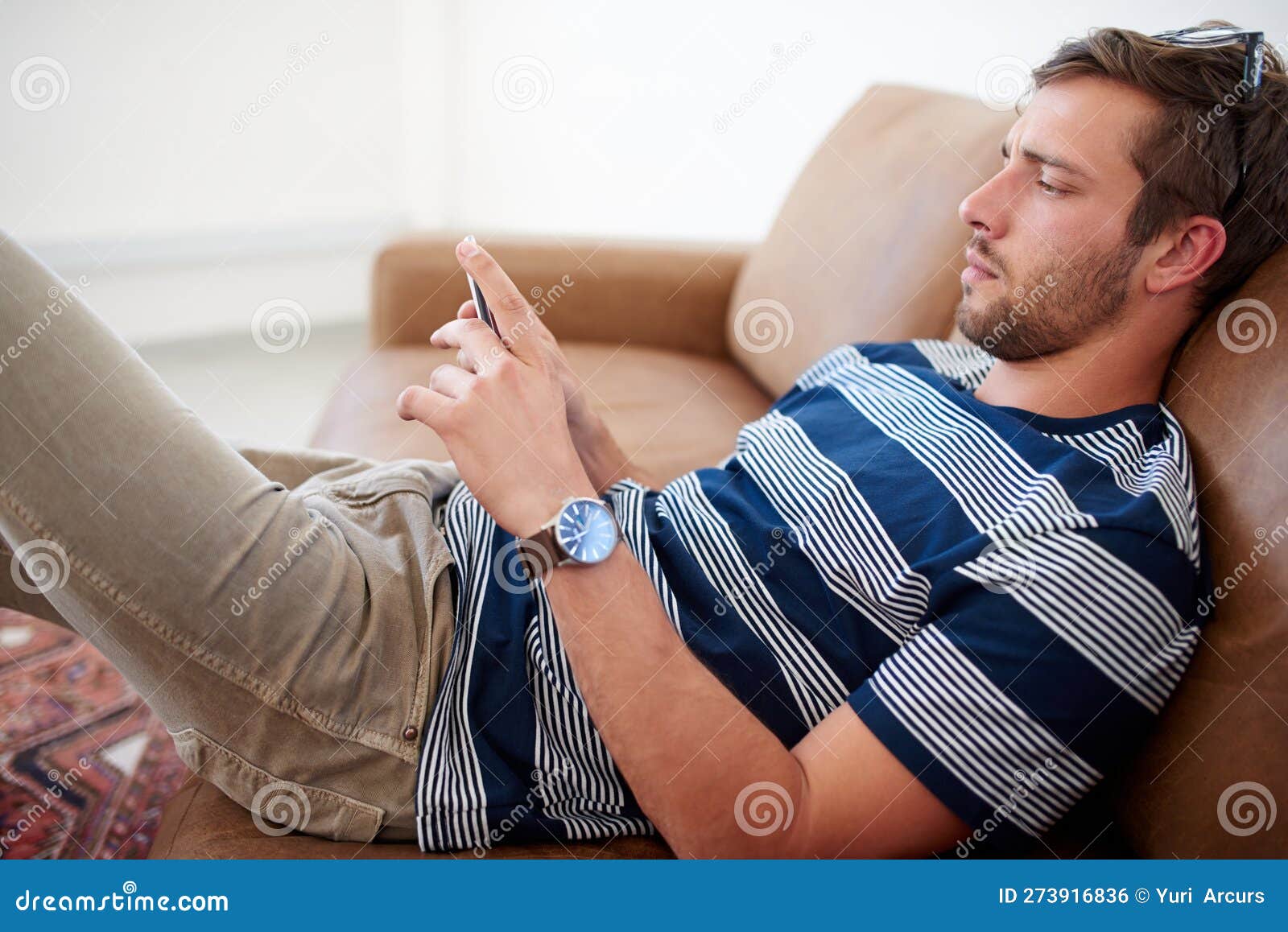 Keeping in Touch with the Latest Apps. Young Man Slouching on a Couch ...
