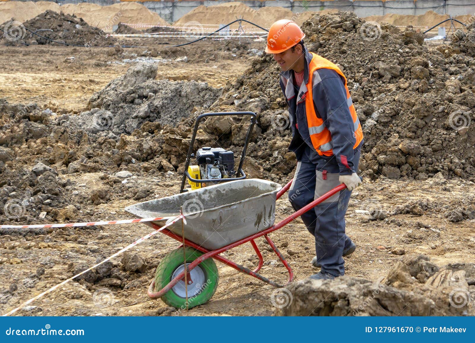 Wheelbarrow With Concrete On A Construction Site, Workers In Uniform ...