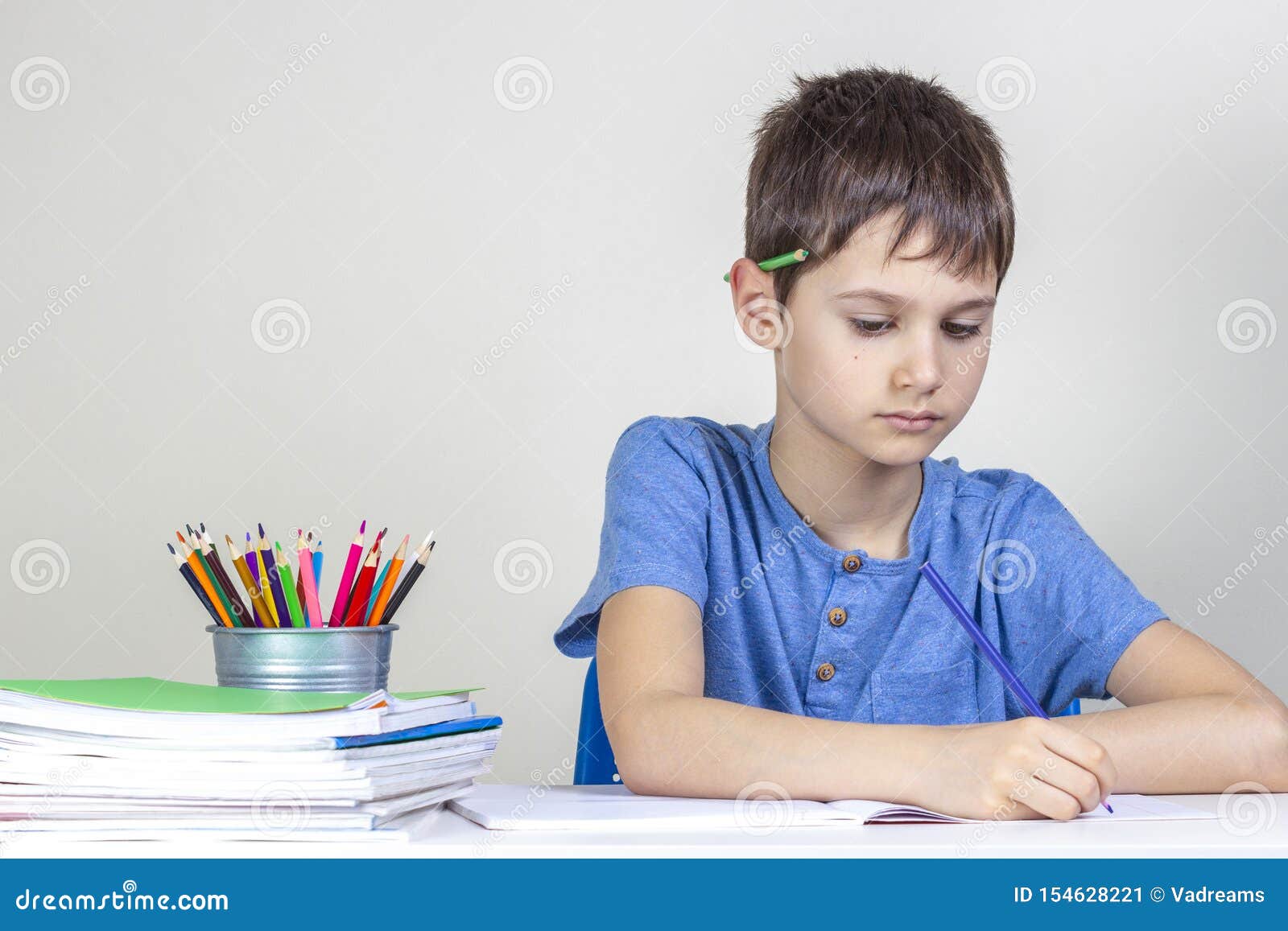 Kid Doing Homework at the Table. Focused Boy with Pencil Behind His Ear ...