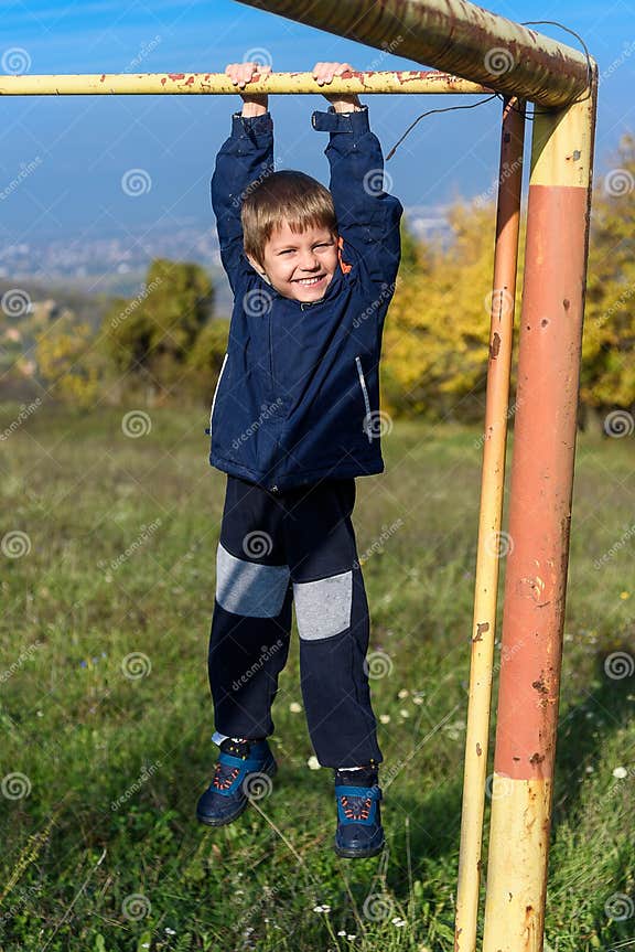 Kid Doing Pull Ups on Sports Ground. Boy Doing Pull Ups Outdoors Stock ...
