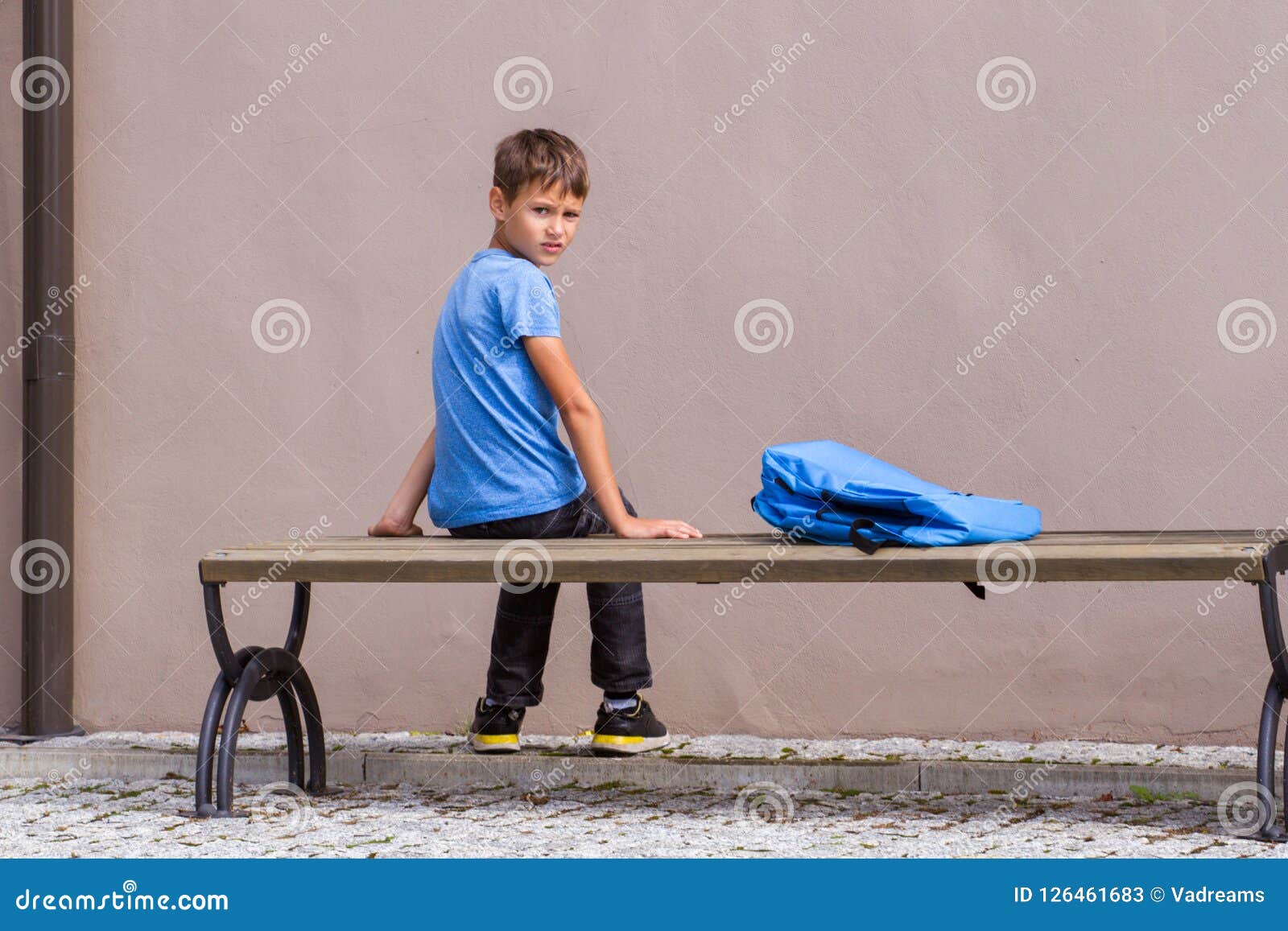Kid Sitting on the Bench Back View, he Turns Around and Look on Camera ...