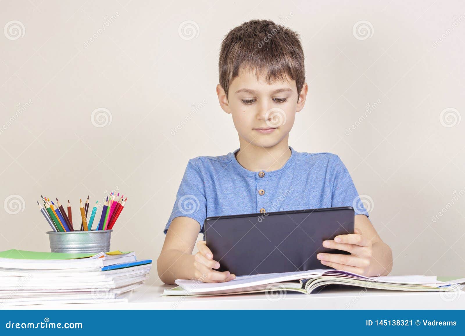 Kid Sitting at Table with Books Notebooks and Using Tablet Computer ...