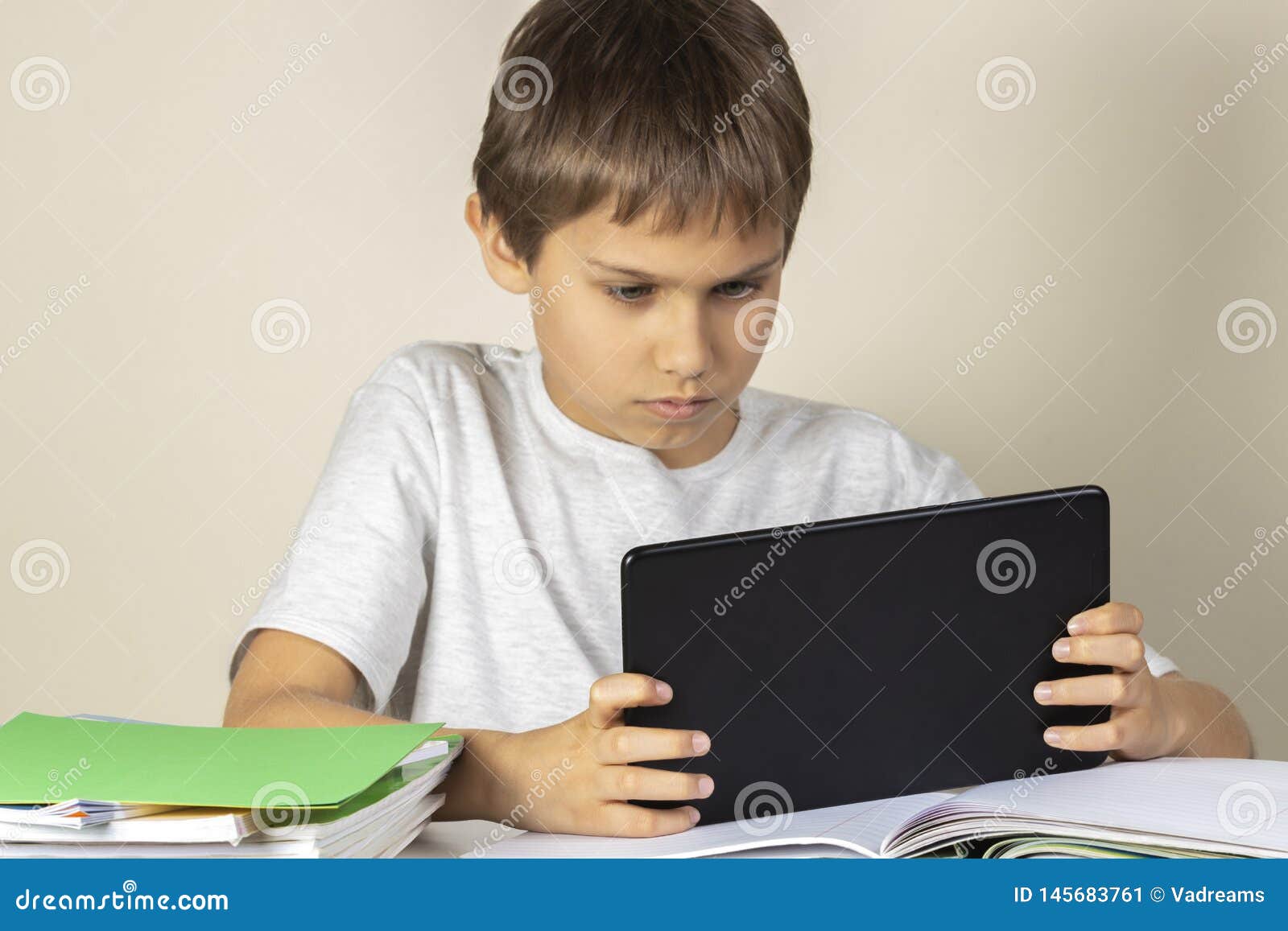Kid Sitting at Table with Books Notebooks and Using Tablet Computer ...