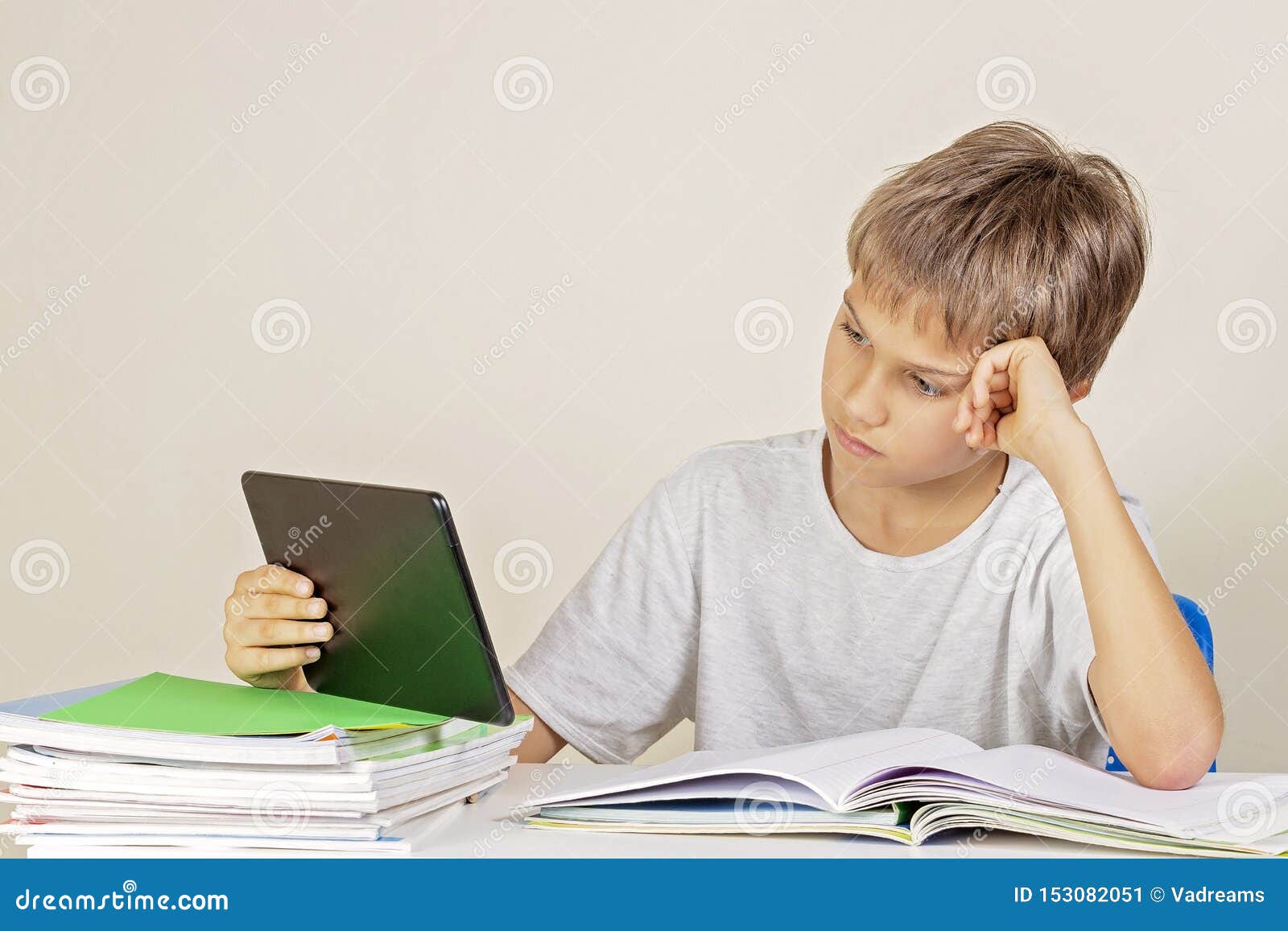 Kid Sitting at Table with Books Notebooks and Using Tablet Computer ...