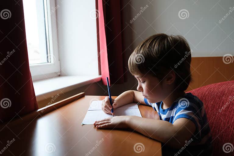 The Kid is Sitting at the Table and Doing Homework. the Child Writes ...