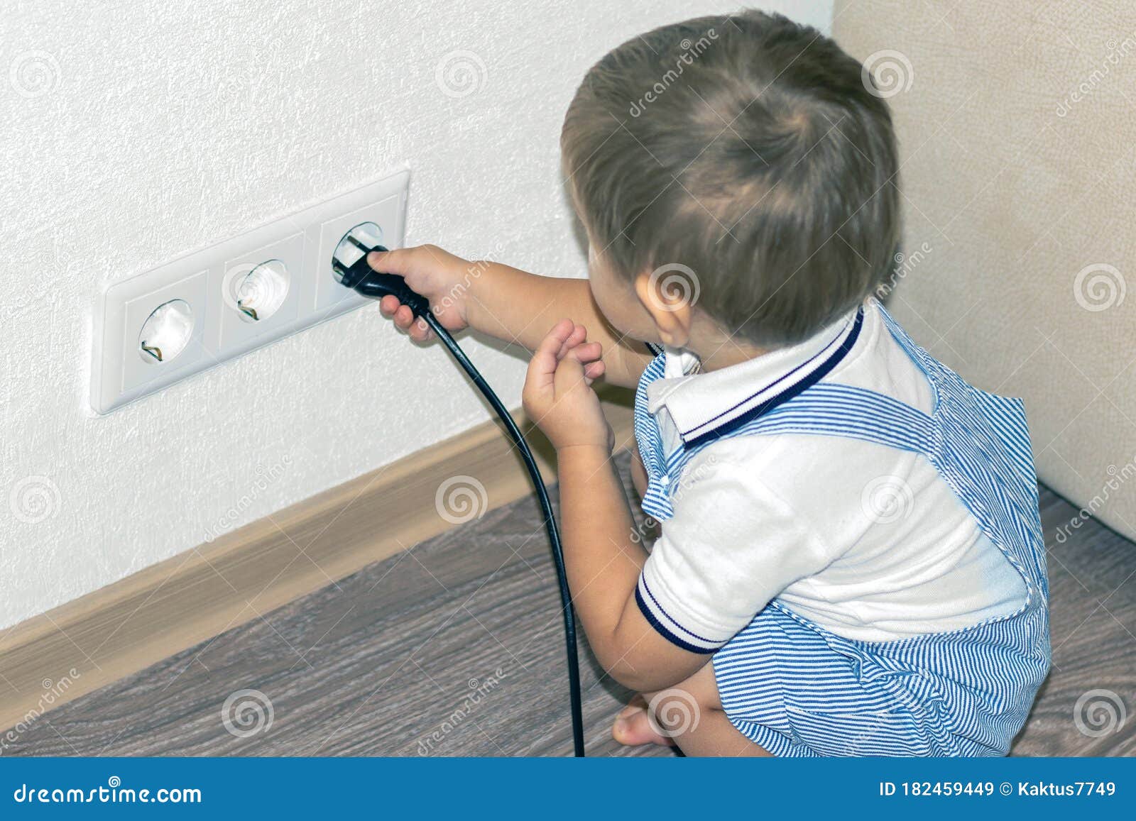 The Kid is Trying To Insert the Plug into an Electrical Outlet. Stock ...