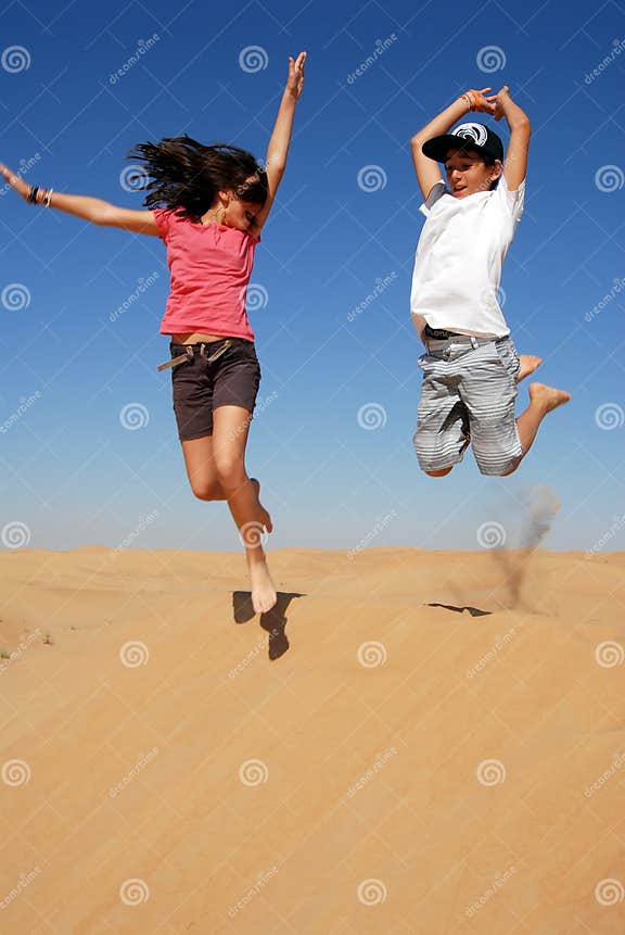 Teens Joyfully Leaping in Desert Dunes Under a Blue Sky, Reveling in ...