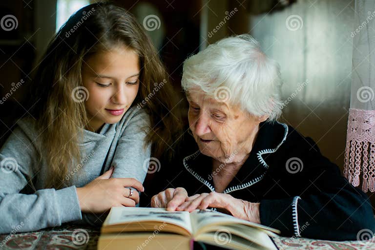 A Kind Silver-haired Grandmother Reads a Book with Her Teenage ... A Kind Silver-haired Grandmother Reads a Book with Her Teenage ...