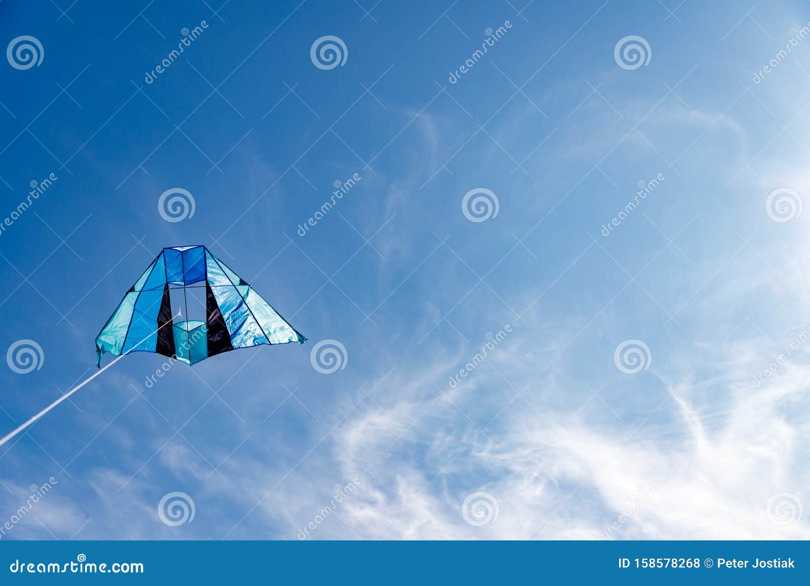 A Kite in Shades of Blue in the Wind on a Blue Sky with Clouds. Feel ...