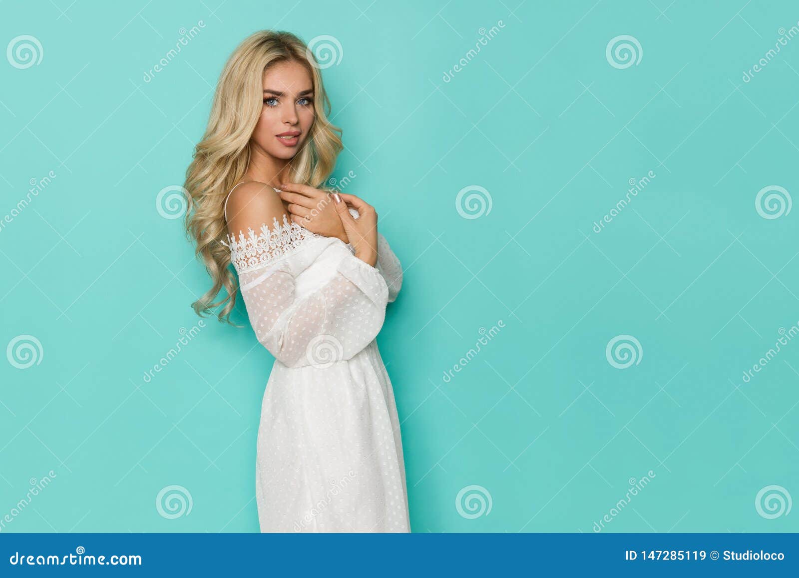 La Belle Femme Blonde Dans La Robe Blanche De Dentelle Pose Avec Des
