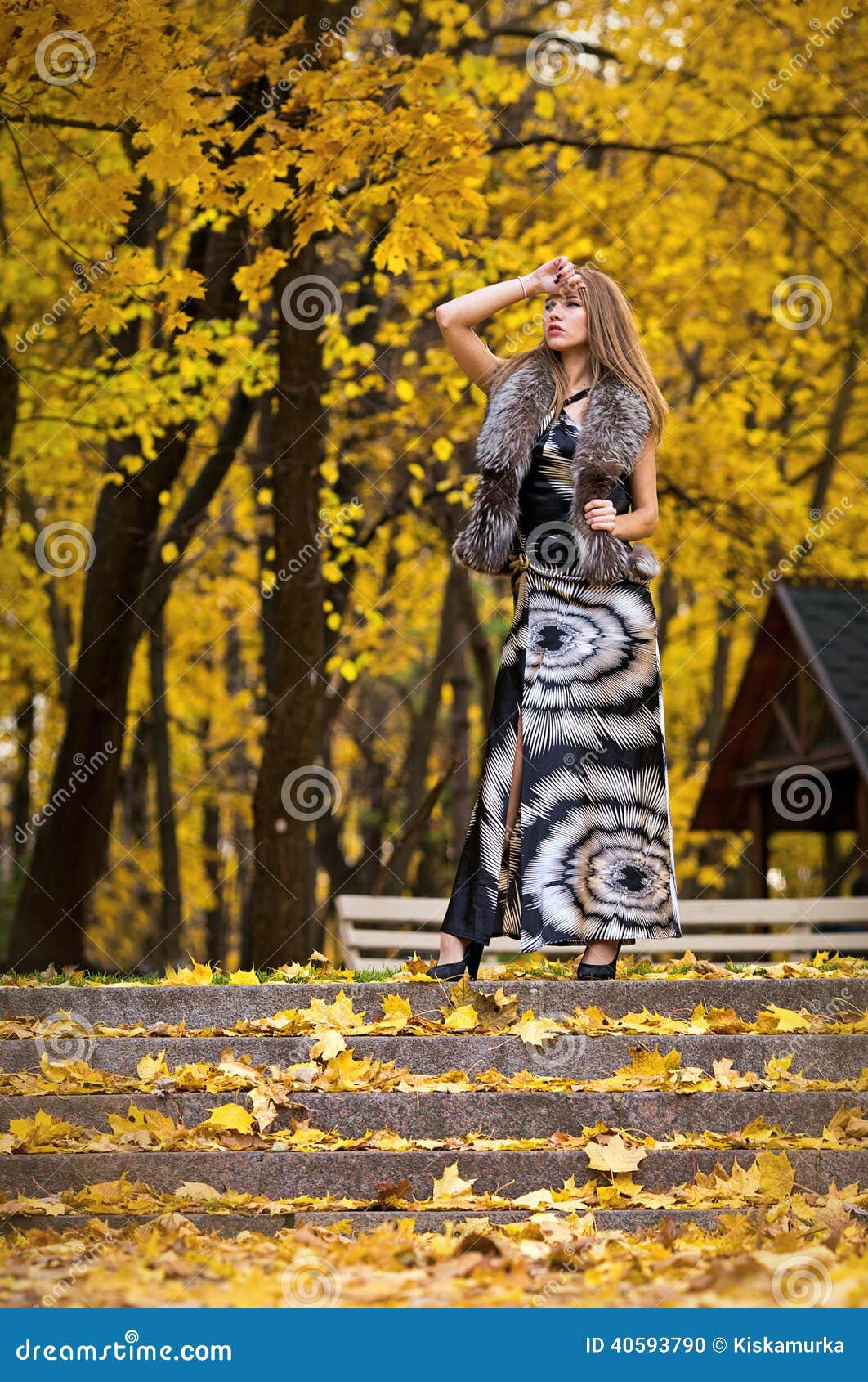 La Belle Fille Blonde Se Tient Sur Un Fond Des Feuilles Jaunes De L