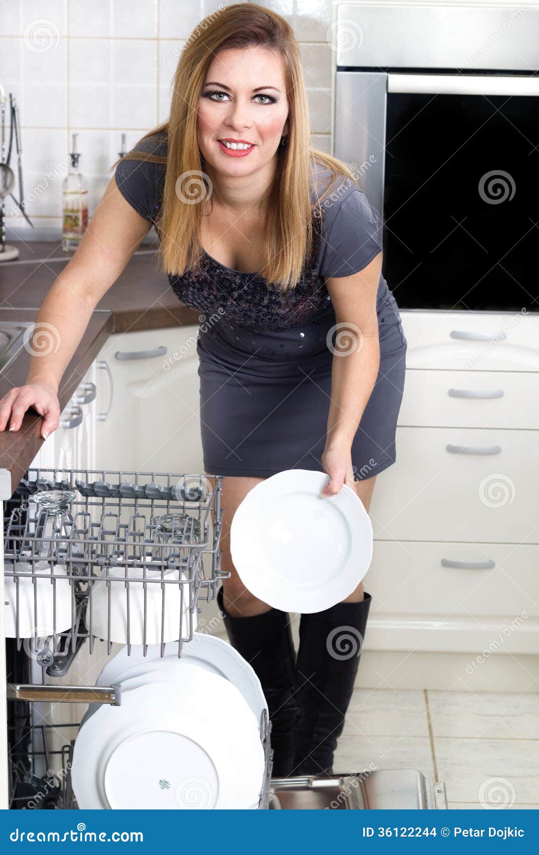 La Femme Au Foyer Sexy Sort Les Plats Du Lave Vaisselle Photo Stock