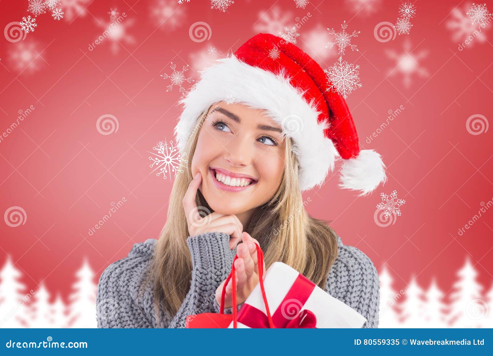 La Femme De Sourire Dans Le Chapeau De Santa Tenant Un Cadeau Mettent