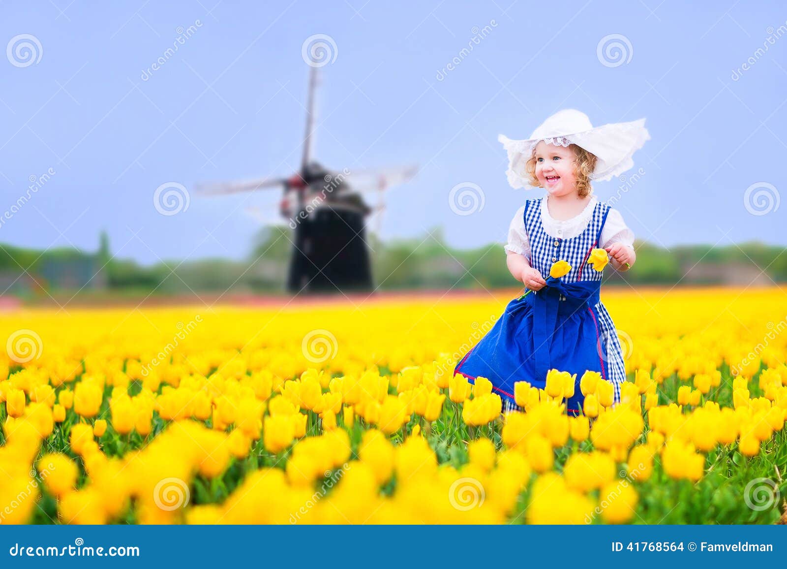 La Ragazza Allegra In Costume Olandese In Tulipani Sistema Con Il Mulino A Vento Fotografia