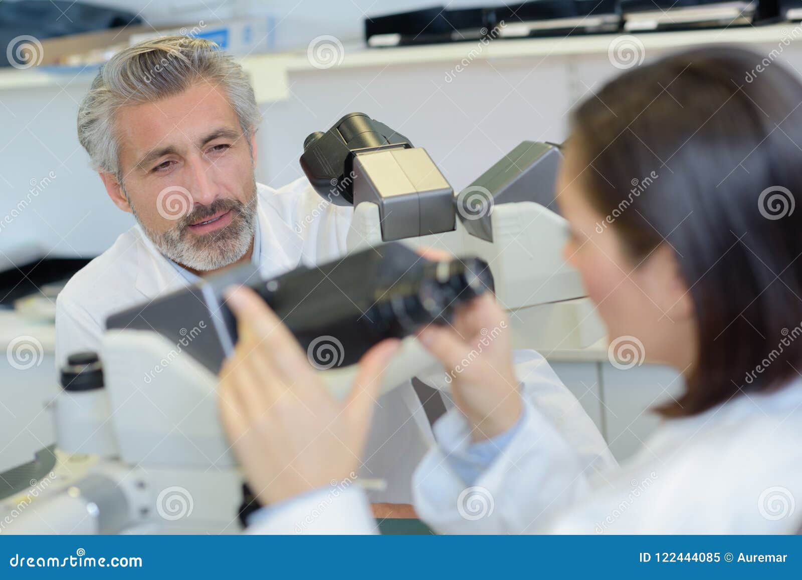 Lab Worker Holding Microscope and Talking To Colleague Stock Image ...