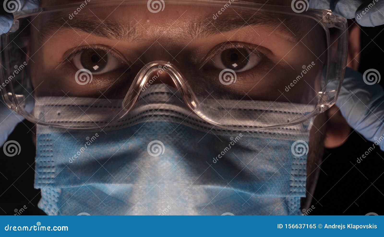 A Lab Worker in a Mask Puts on Protective Work Glasses for Working in ...