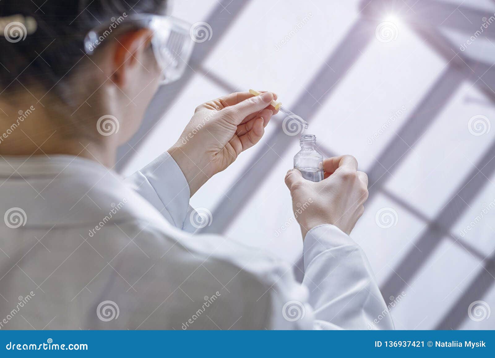 A Laboratorian Assistant is Operating with a Pipette and a Bottle with ...