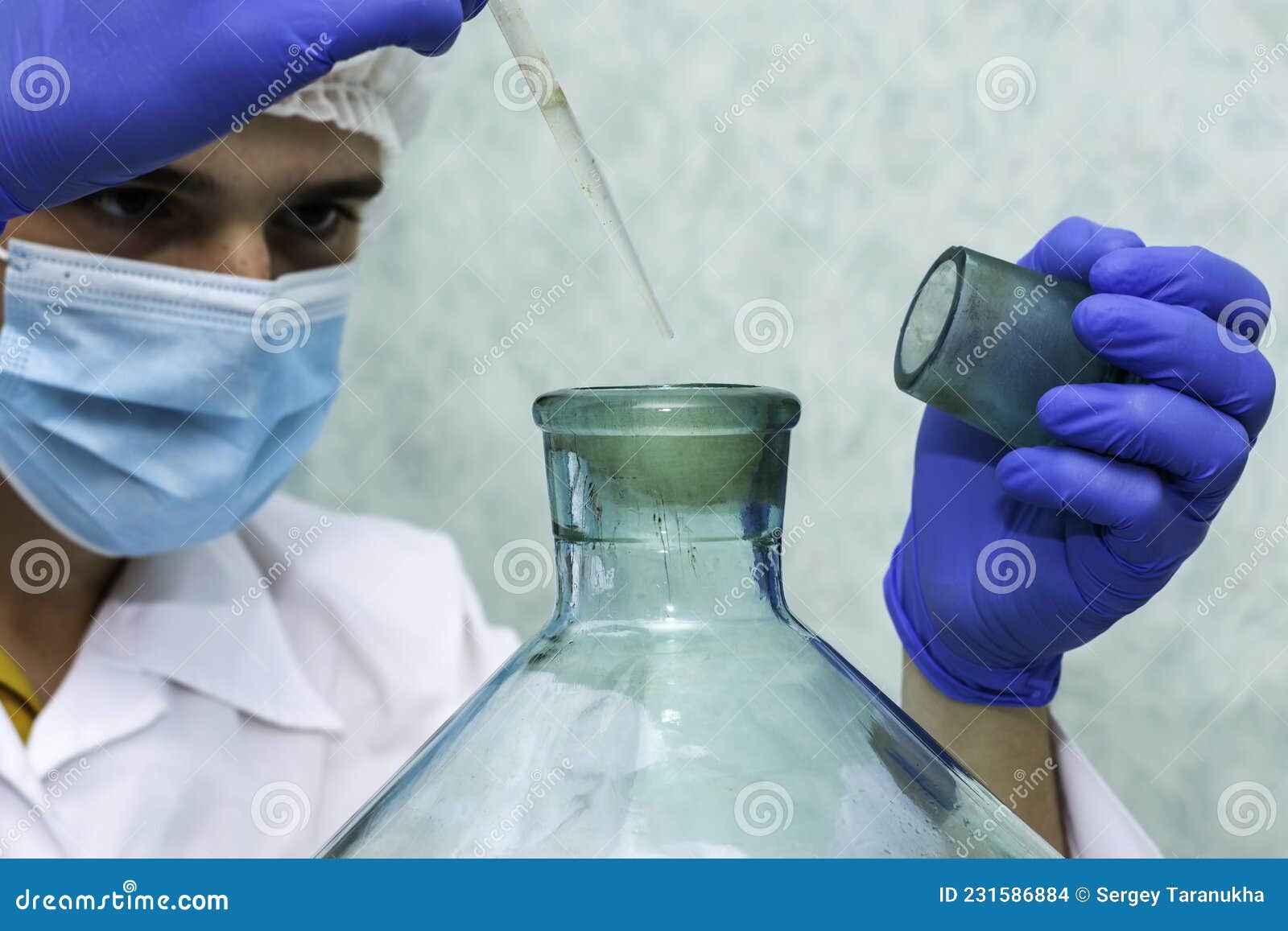A Laboratory Assistant in a White Lab Coat, Protective Mask, Gloves and ...