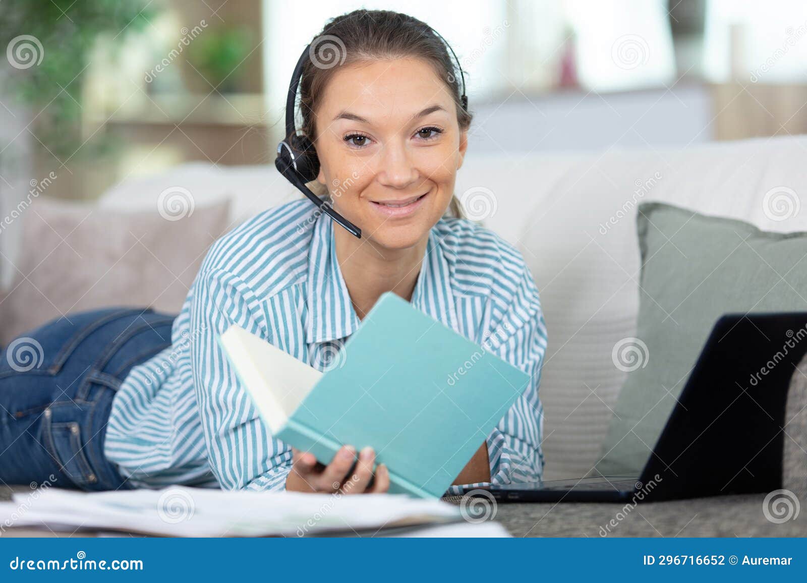 Lady on Couch Wearing Headset with Open Book and Laptop Stock Photo ...