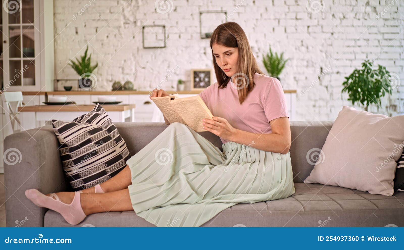 Lady Sitting on a Sofa and Reading Her Notes from Notebook Stock Photo ...