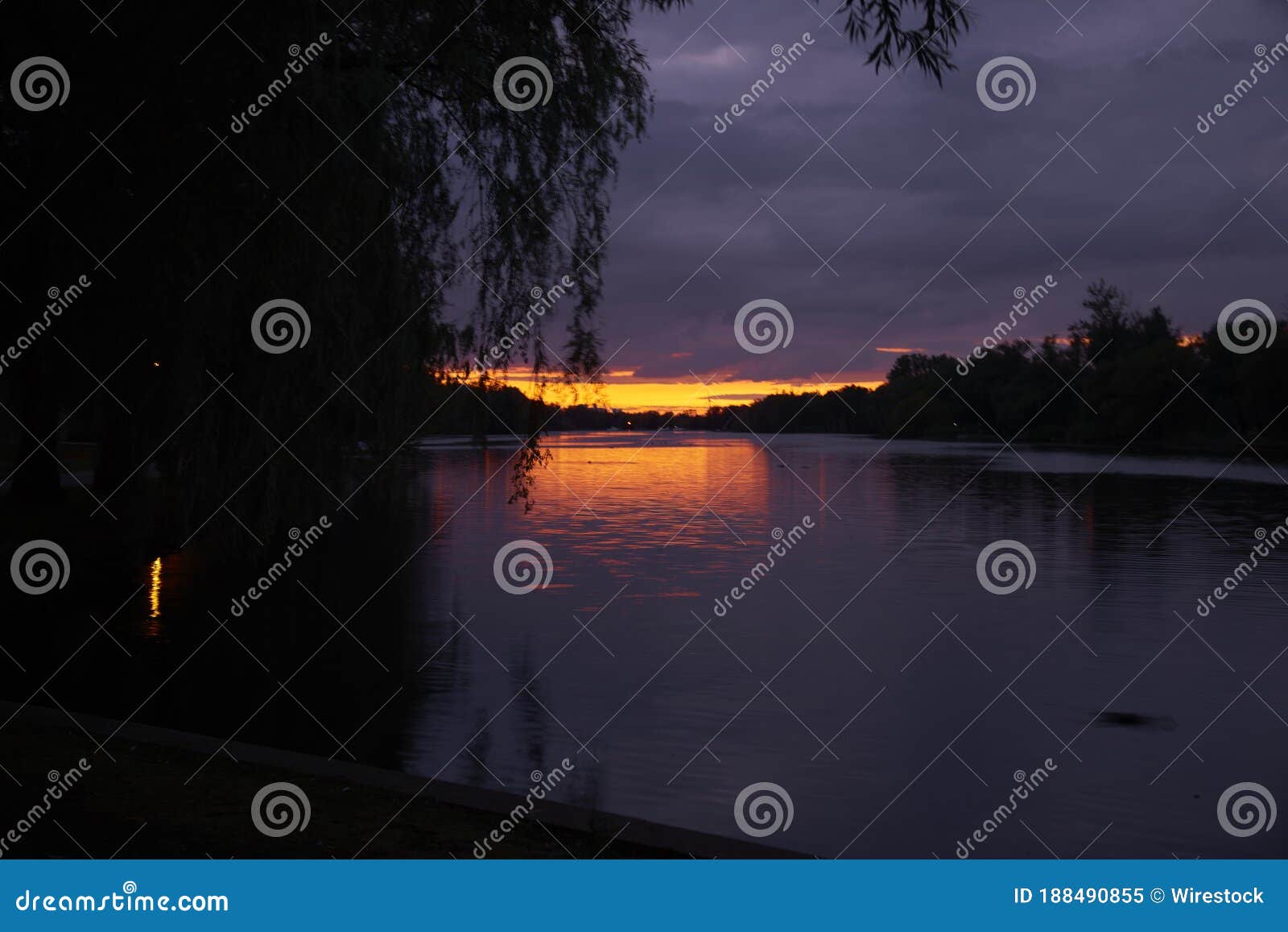 Lake Gleaming Under the Yellow Sunset Piercing through the Cloudy Sky ...