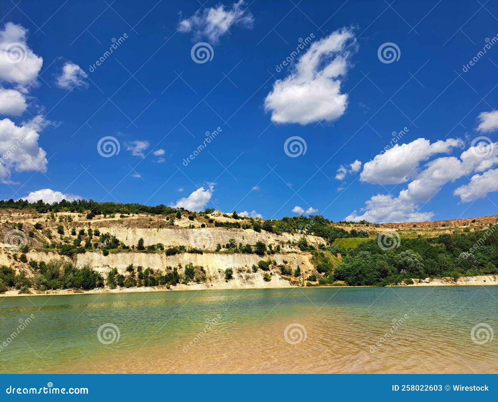 Lake Surrounded by Cliffs and Trees Under a Blue Sky Stock Image ...