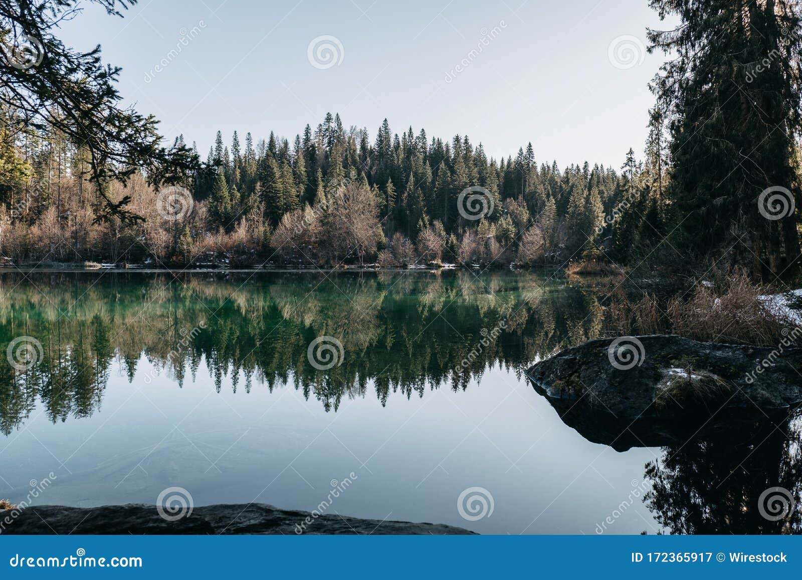 Lake Surrounded by Rocks and Forests with Trees Reflecting on the Water ...
