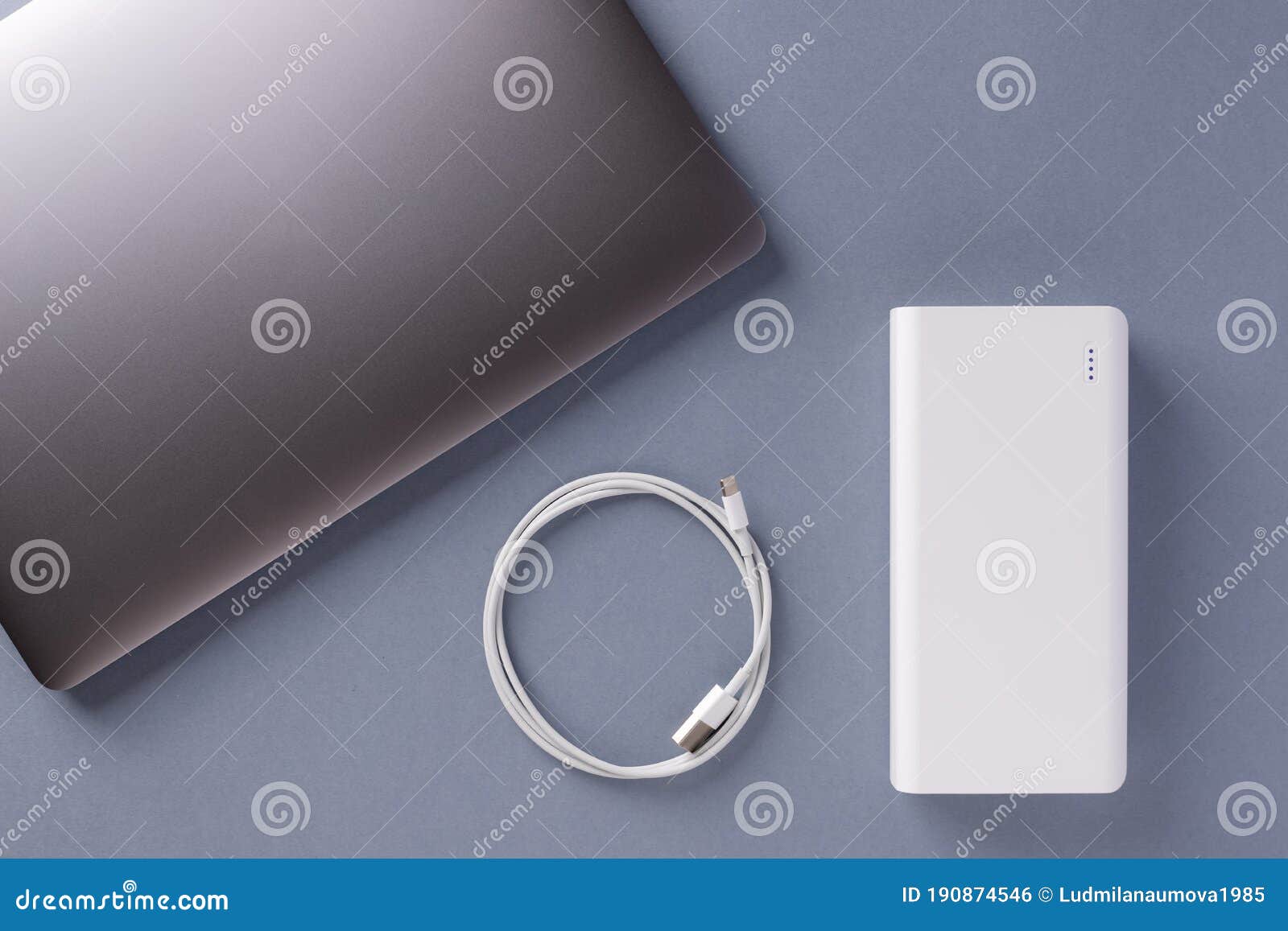 Laptop Computer, Power Bank Charger and Usb Cable on a Blue Background ...