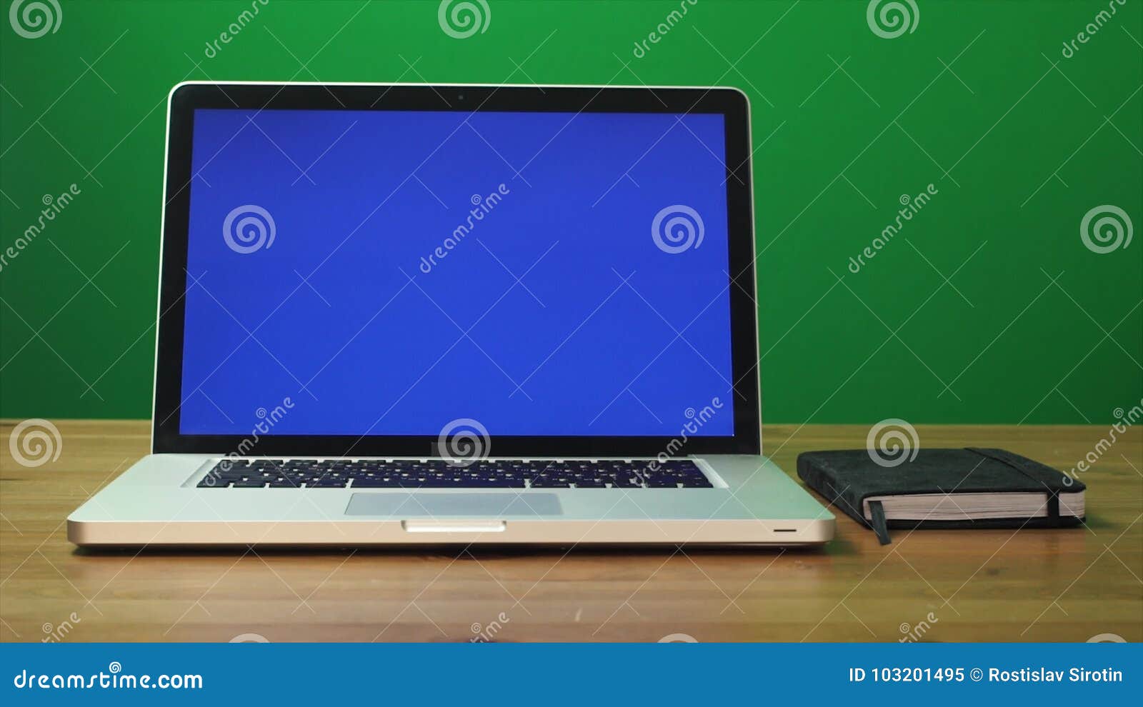 Laptop with a Green Screen and Black Notepad on Table. Green Screen ...