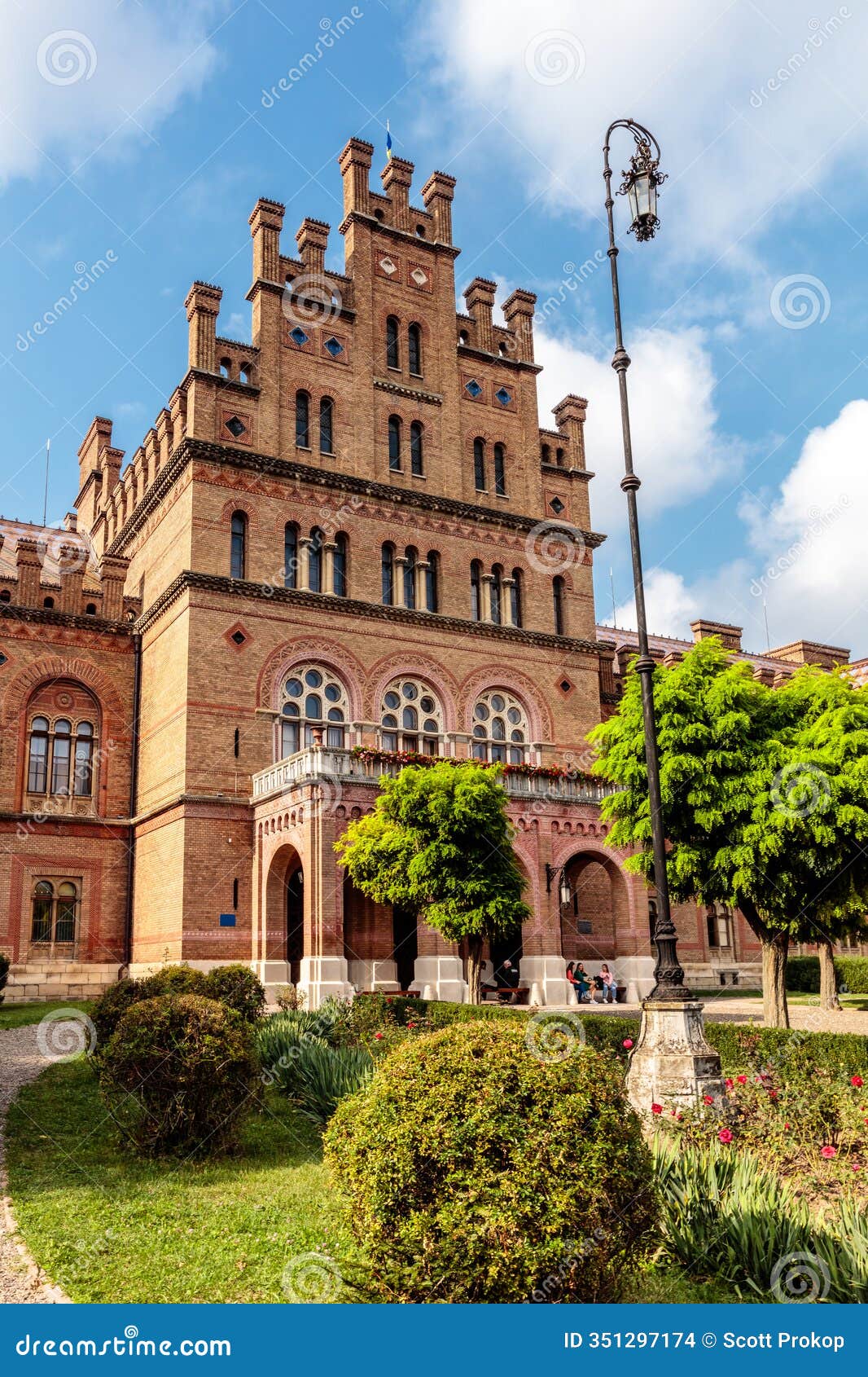 A Large Brick Building with a Clock Tower and a Lamp Post in Front of ...