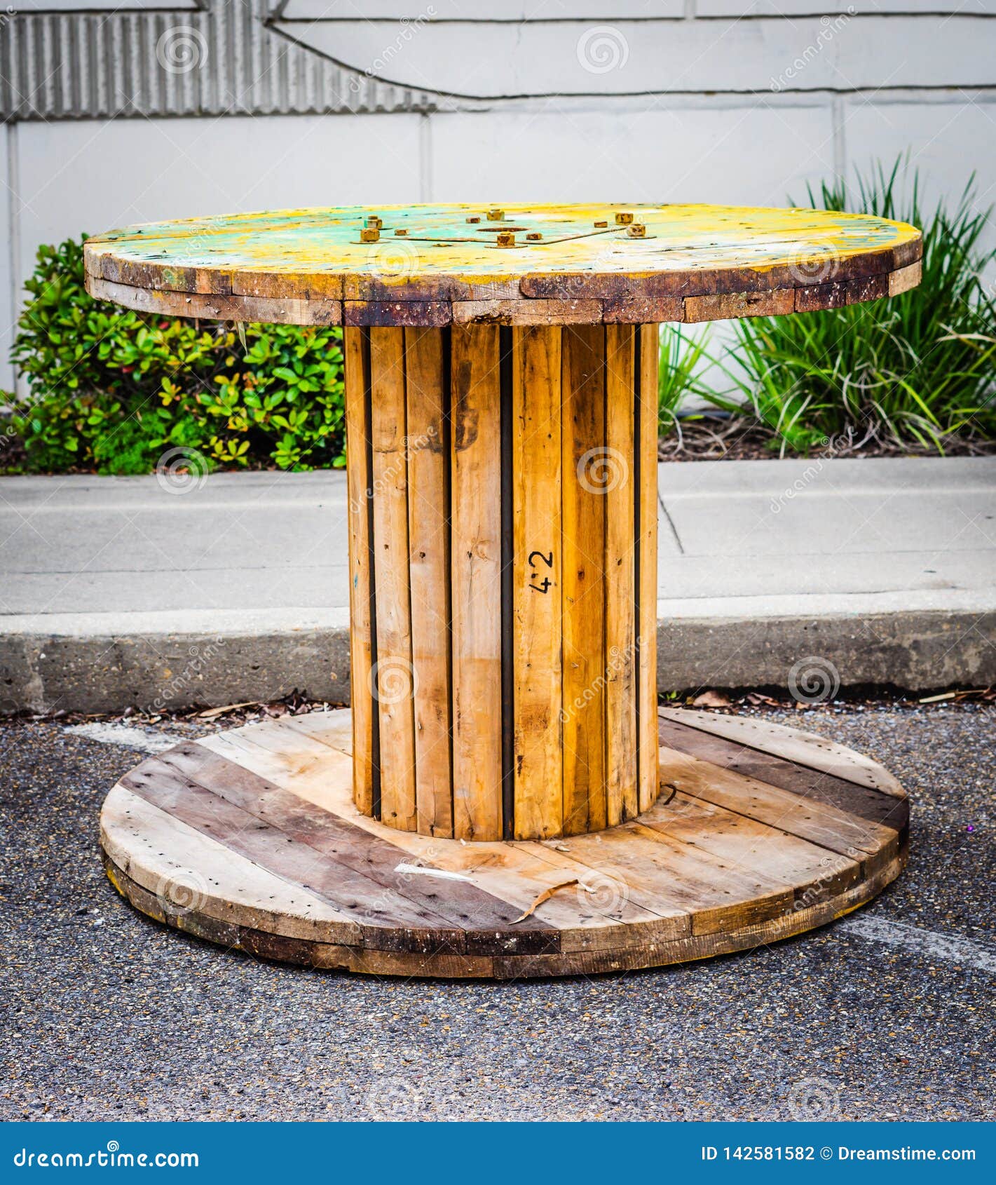 Large Empty Wooden Spool on Asphalt, and a White Stripped Pattern Wall ...