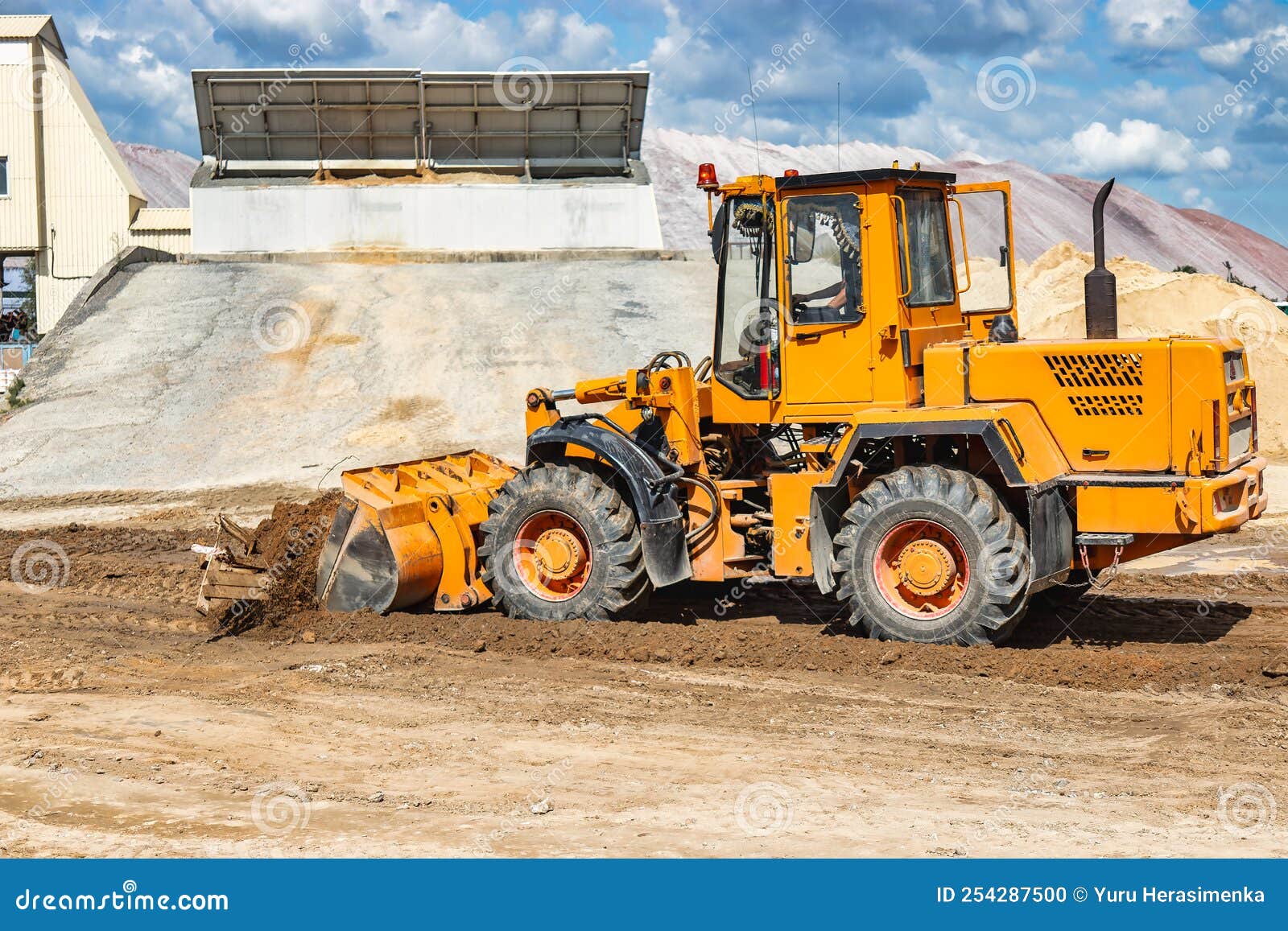 A Large Front Loader Pours Sand into a Pile at a Construction Site ...